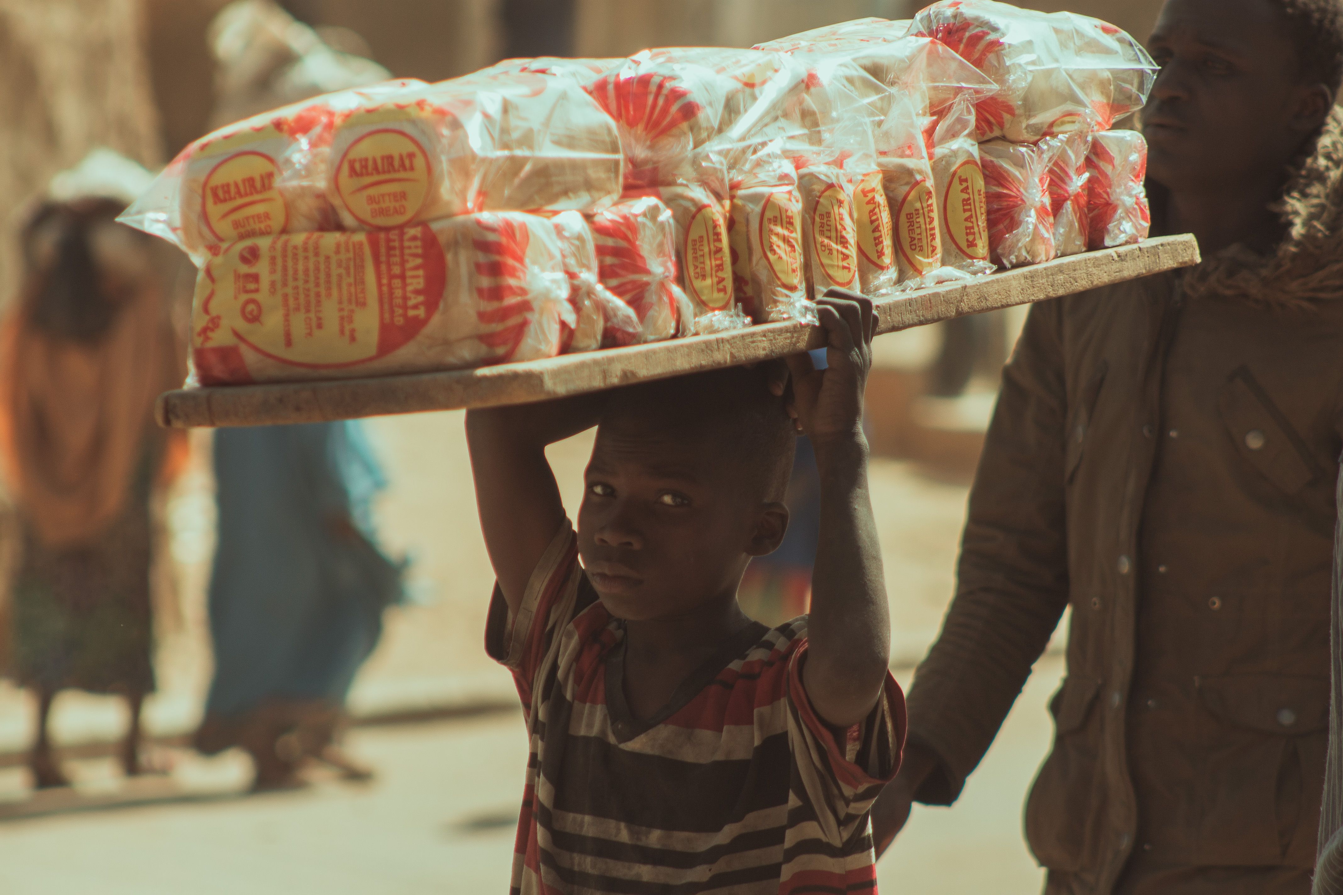 Young Vendor Carrying Bread on the Street · Free Stock Photo
