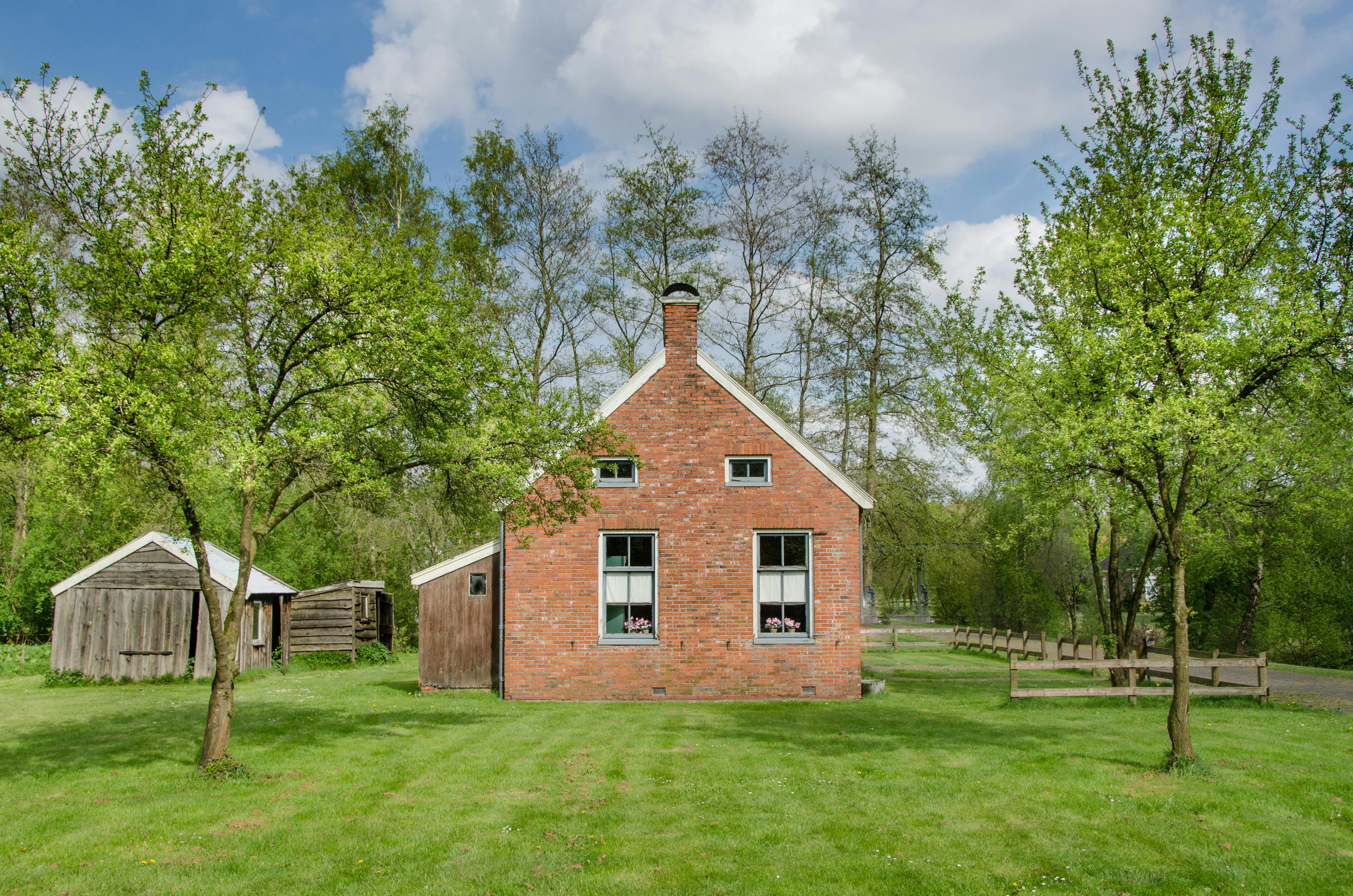 Brown Brick House Surrounded by Green Trees and Grass · Free Stock Photo