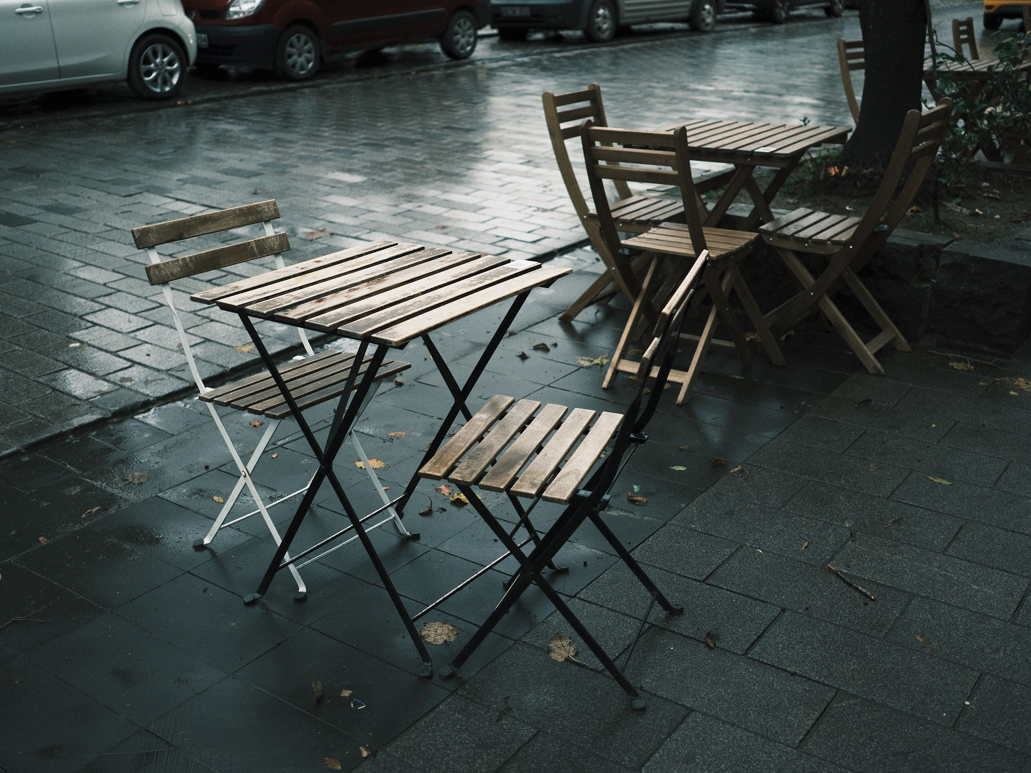 Moody Outdoor Café Tables on Wet Pavement · Free Stock Photo