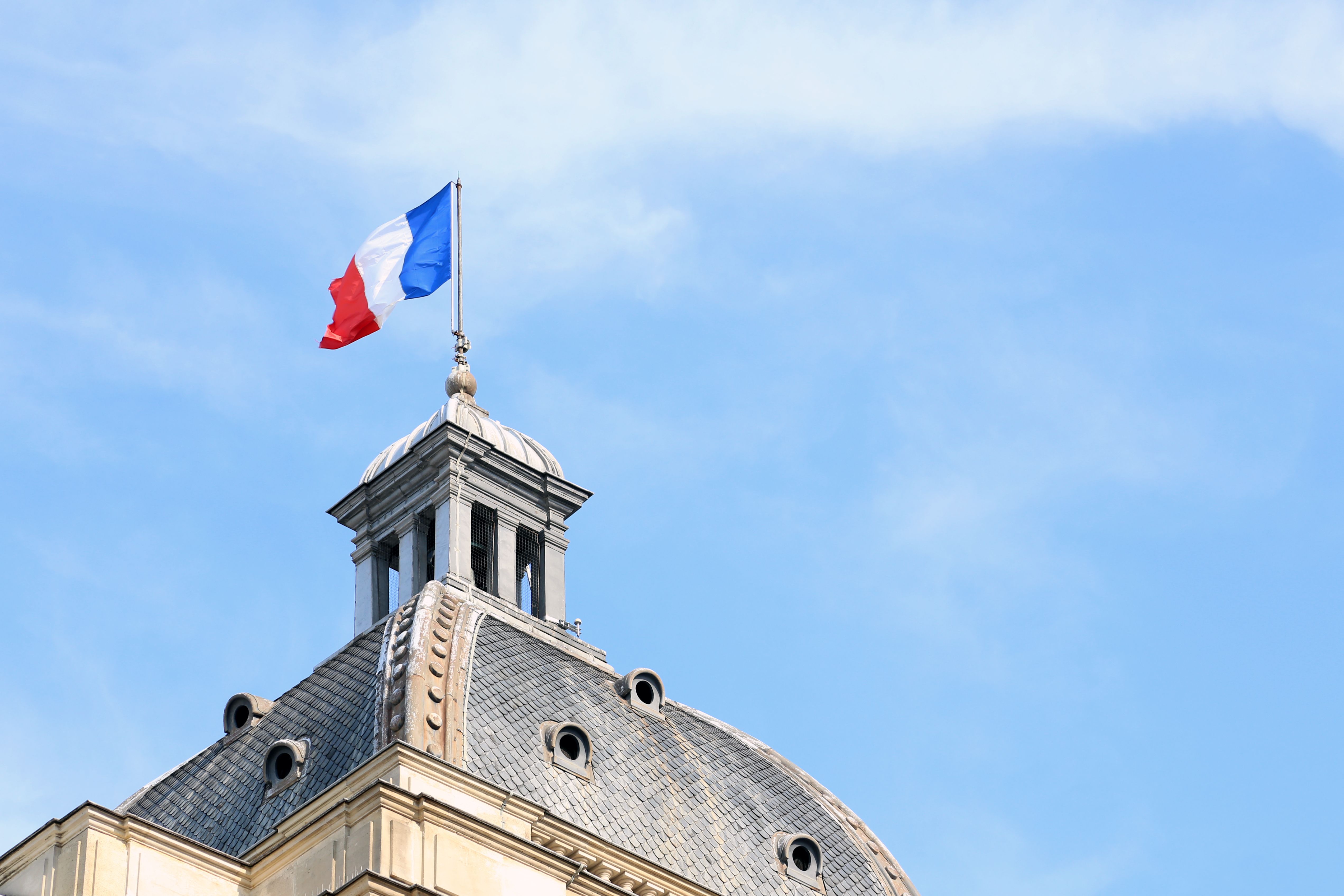 French Flag atop Historic Parisian Building · Free Stock Photo