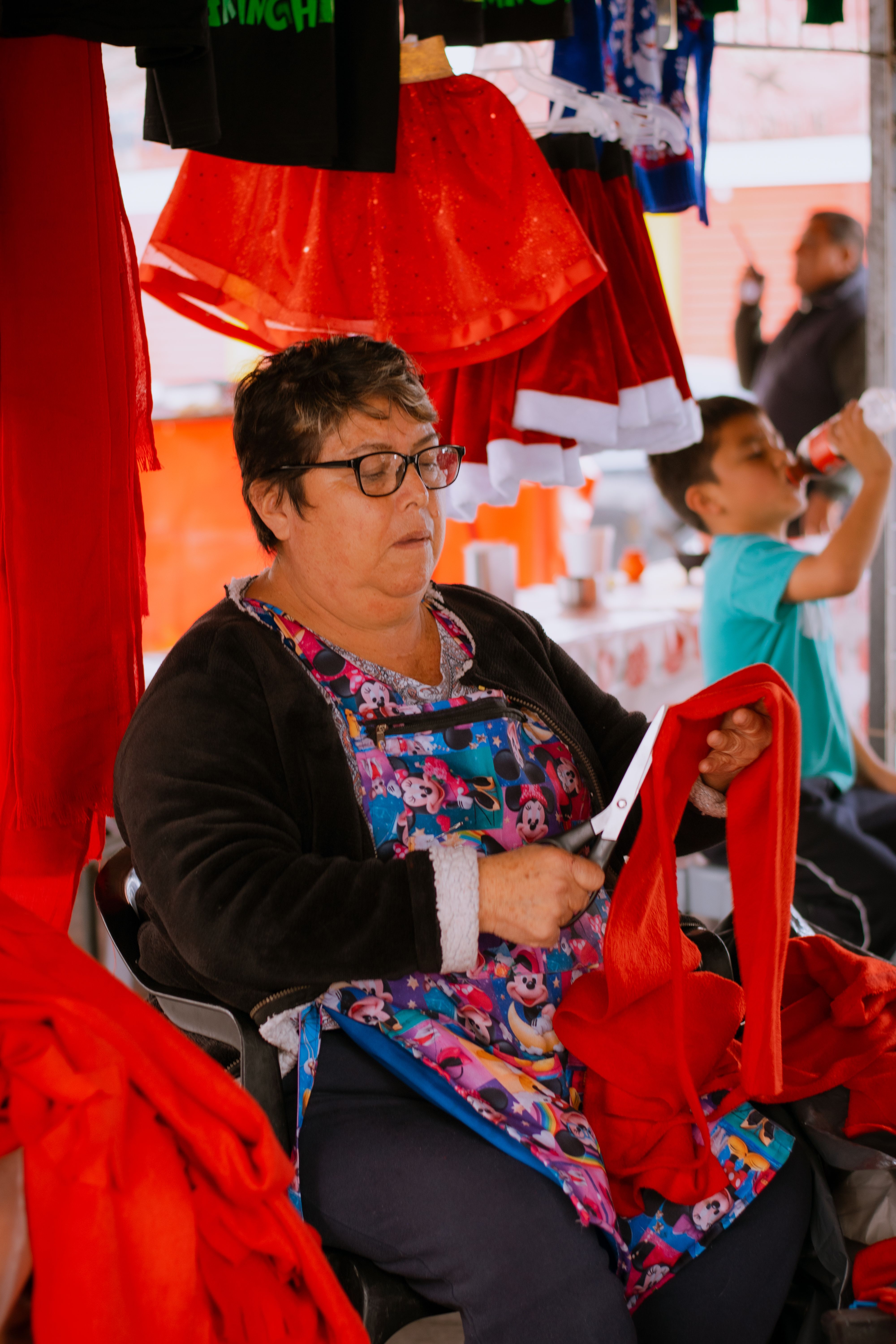 Woman Sewing Red Fabric at Street Market · Free Stock Photo