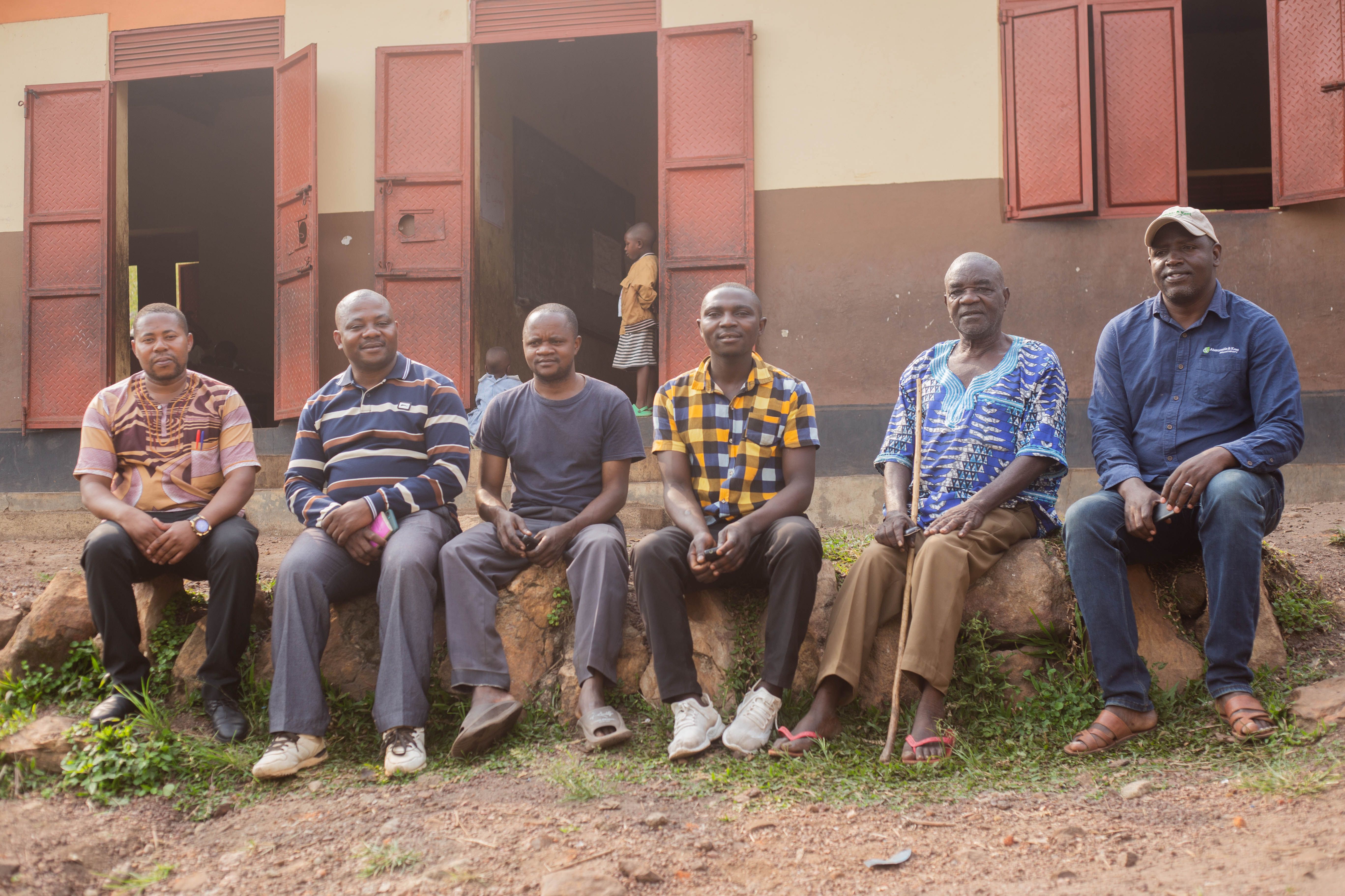Group of Men Sitting Outside Community Building · Free Stock Photo