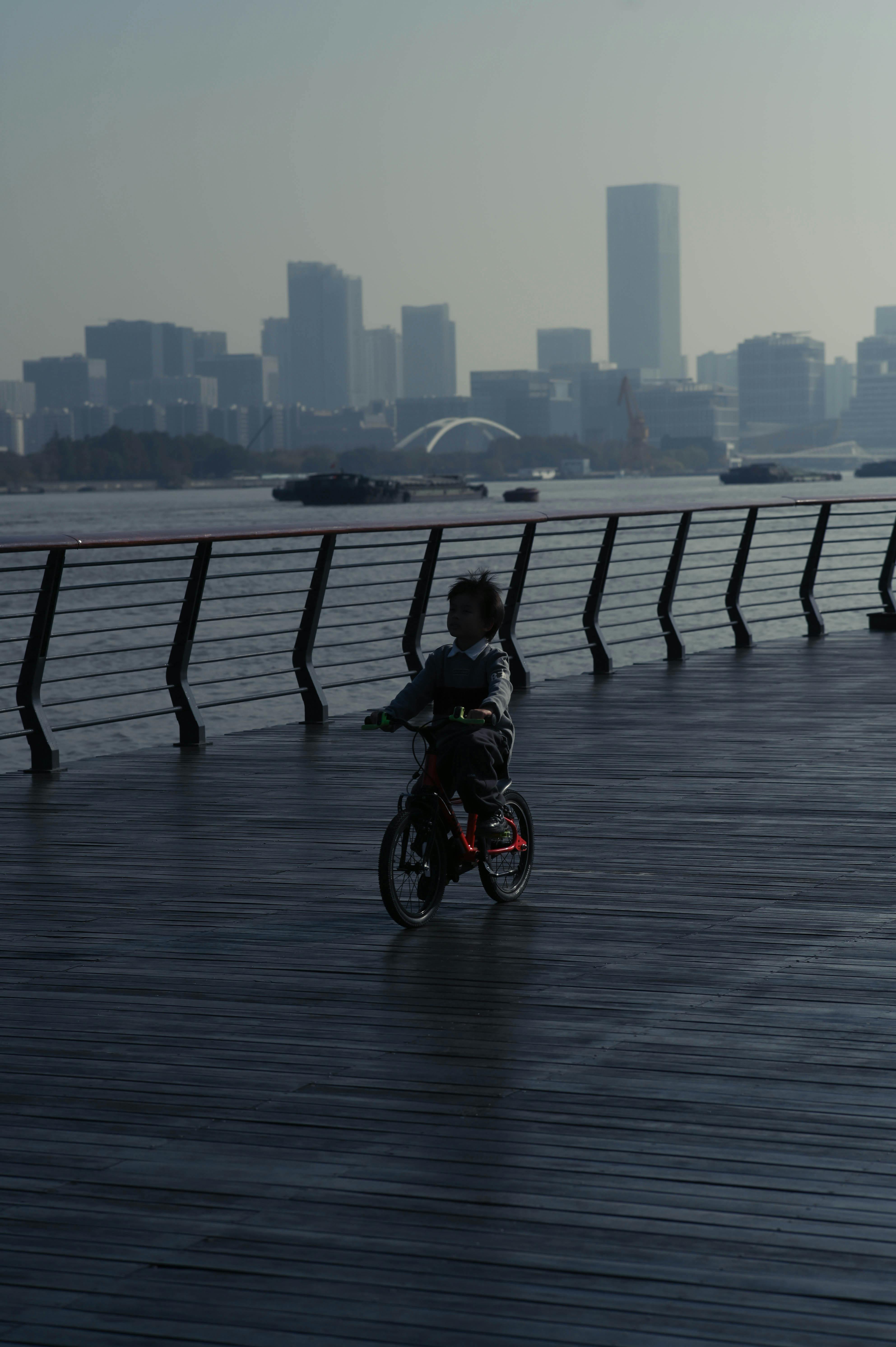 Child Cycling on Waterfront Boardwalk at Dusk · Free Stock Photo