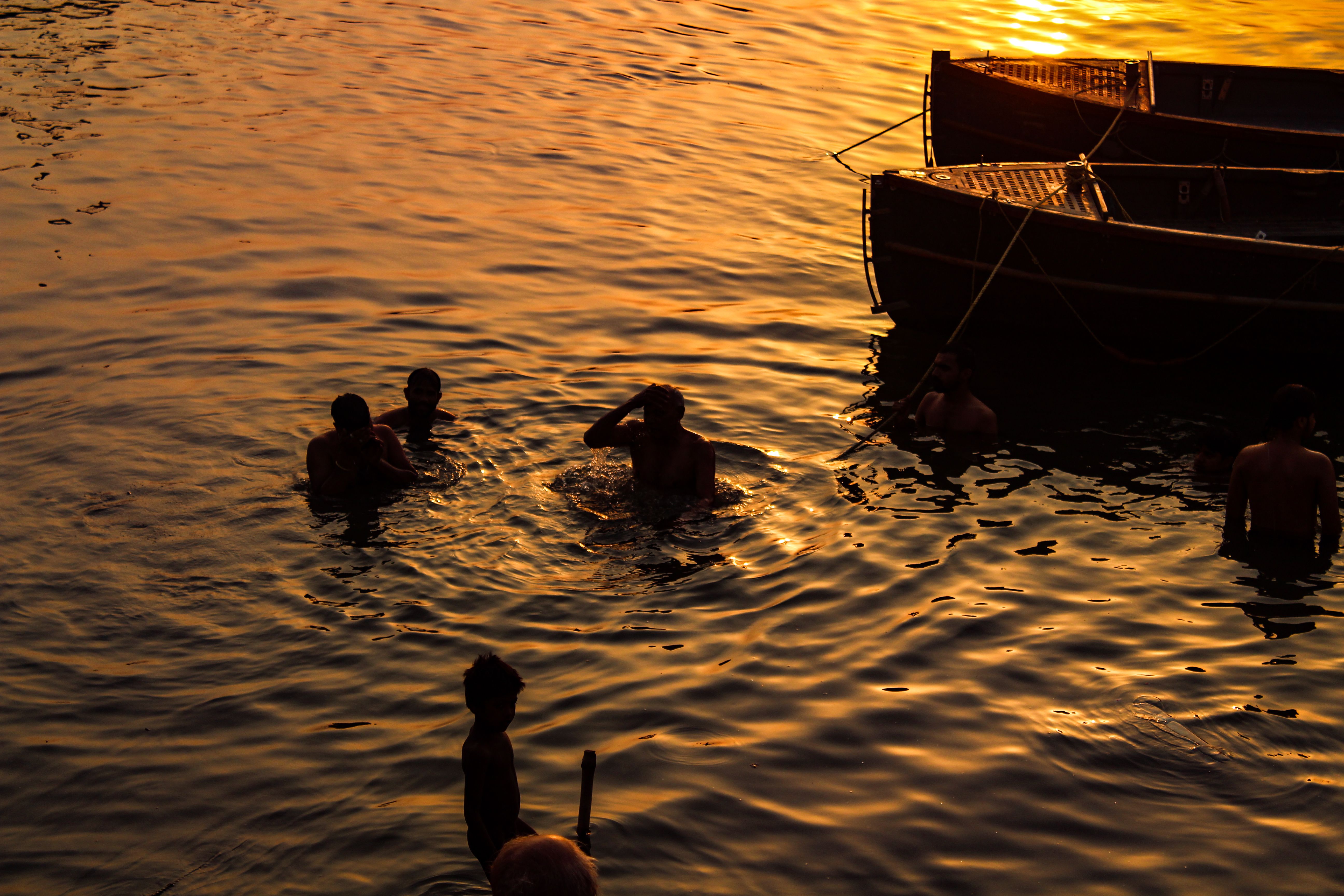 Serene Sunset Swim by the Boats · Free Stock Photo