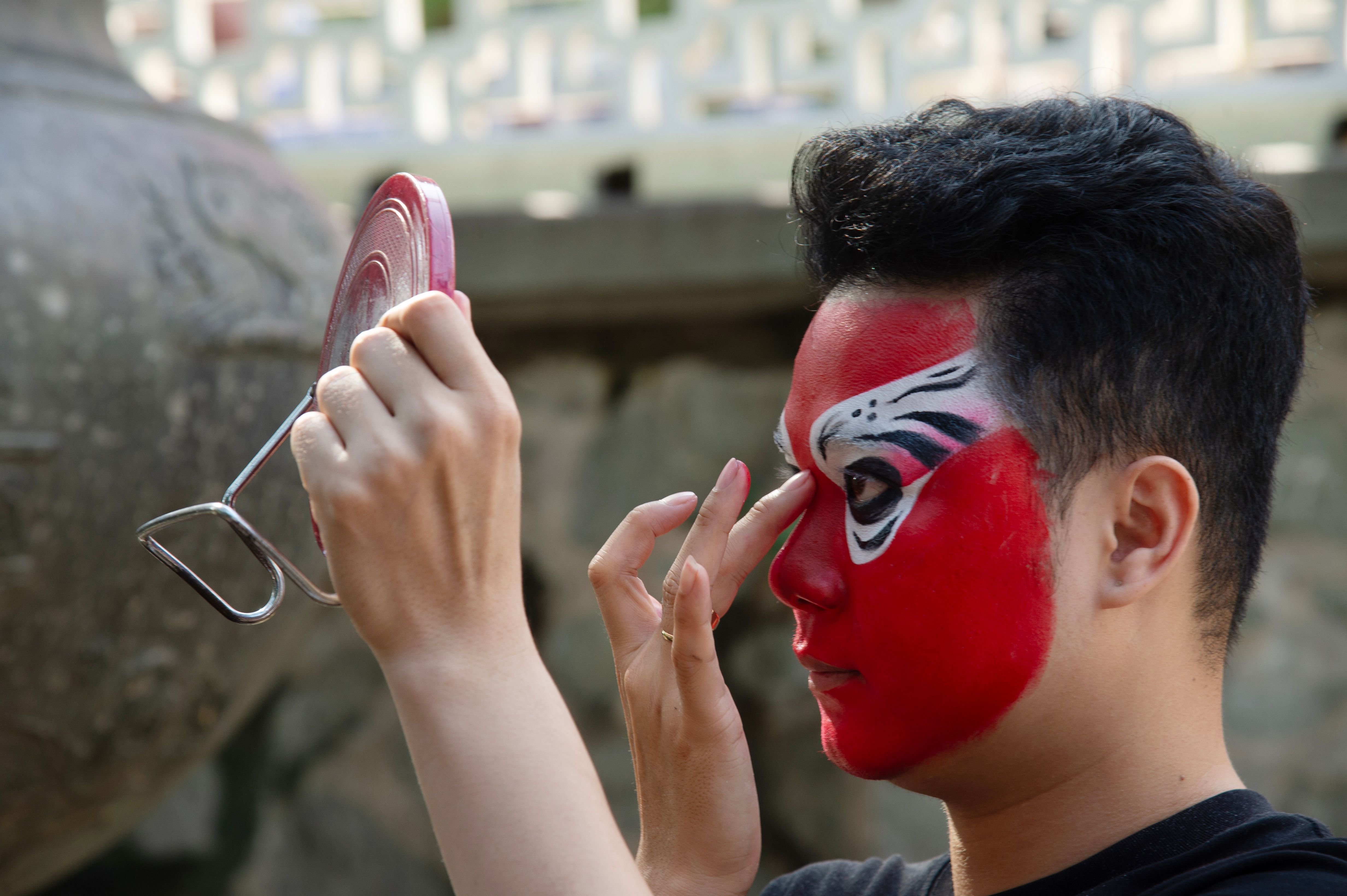 Man Applying Chinese Opera Makeup Outdoors · Free Stock Photo