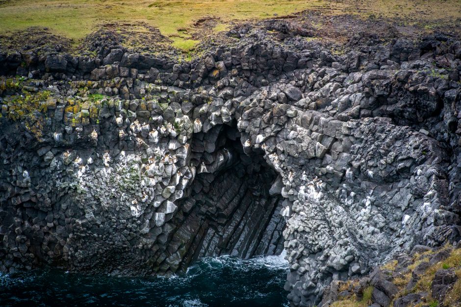 Dramatic view of basalt rock formations in Iceland with crashing waves.
