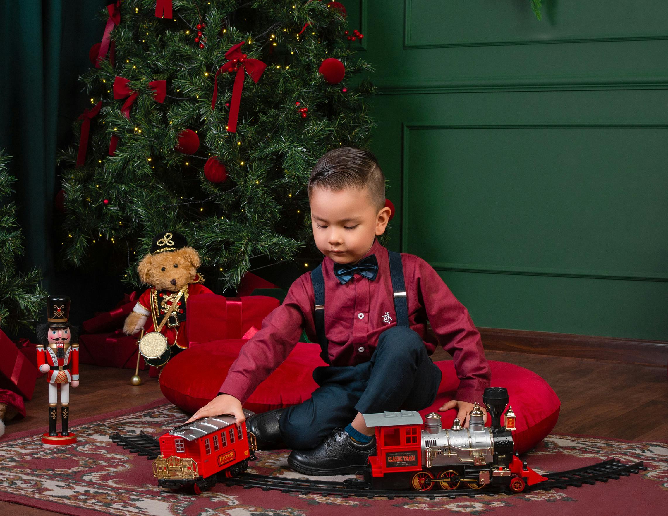 Child Playing with Train Set by Christmas Tree · Free Stock Photo