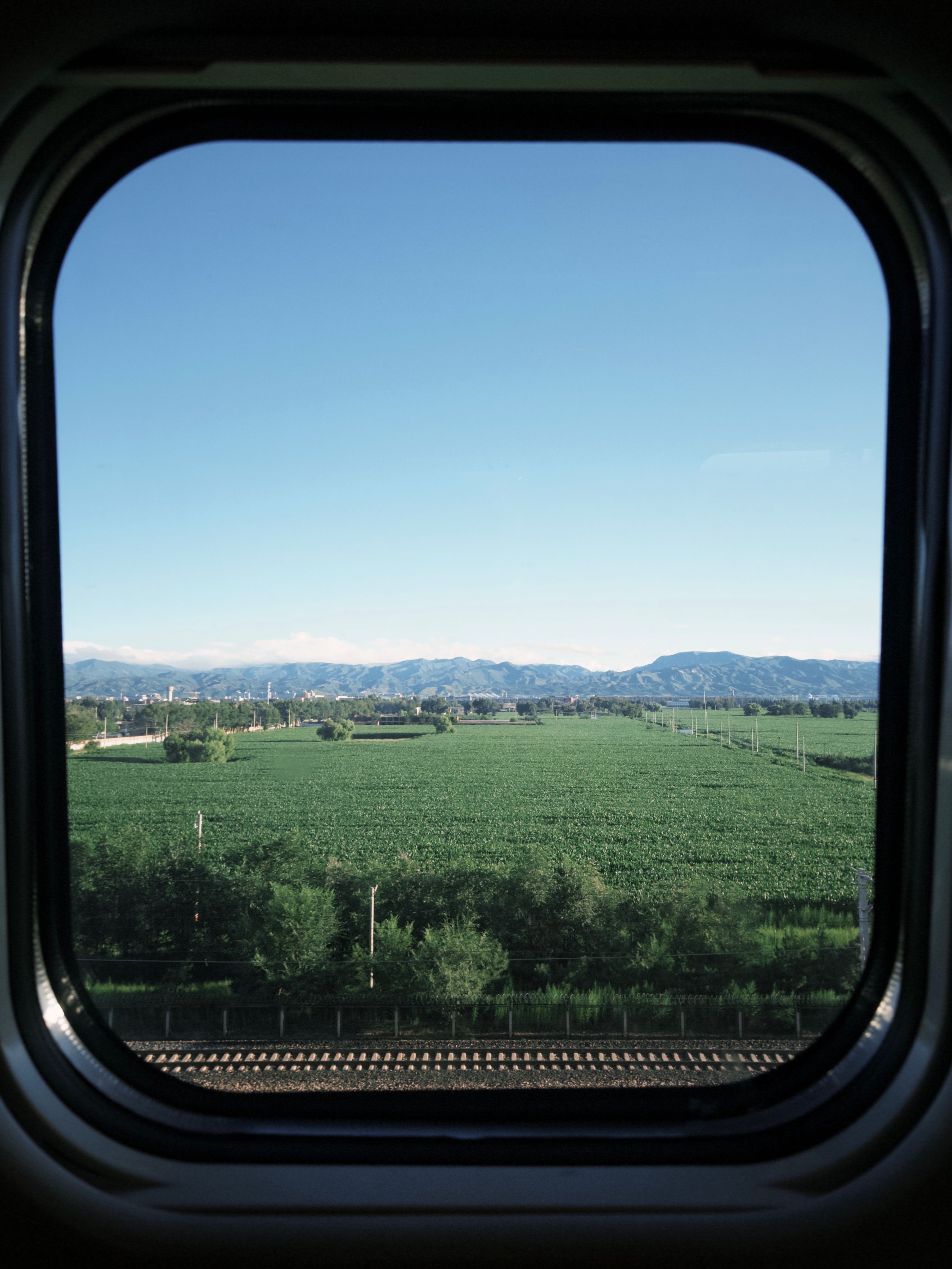 Scenic Train Window View of Green Fields · Free Stock Photo