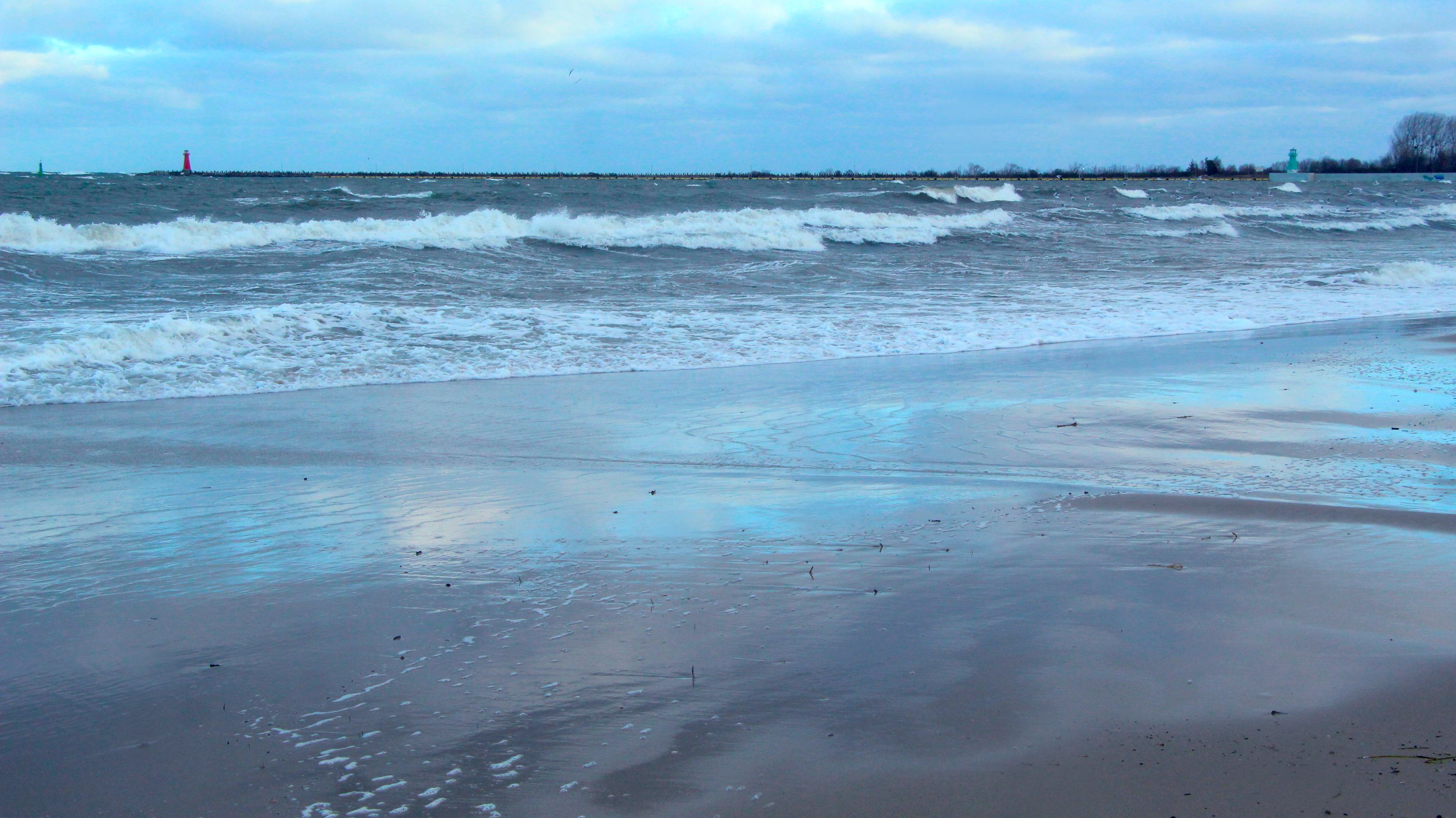 Serene Beachfront with Gentle Waves and Lighthouses · Free Stock Photo