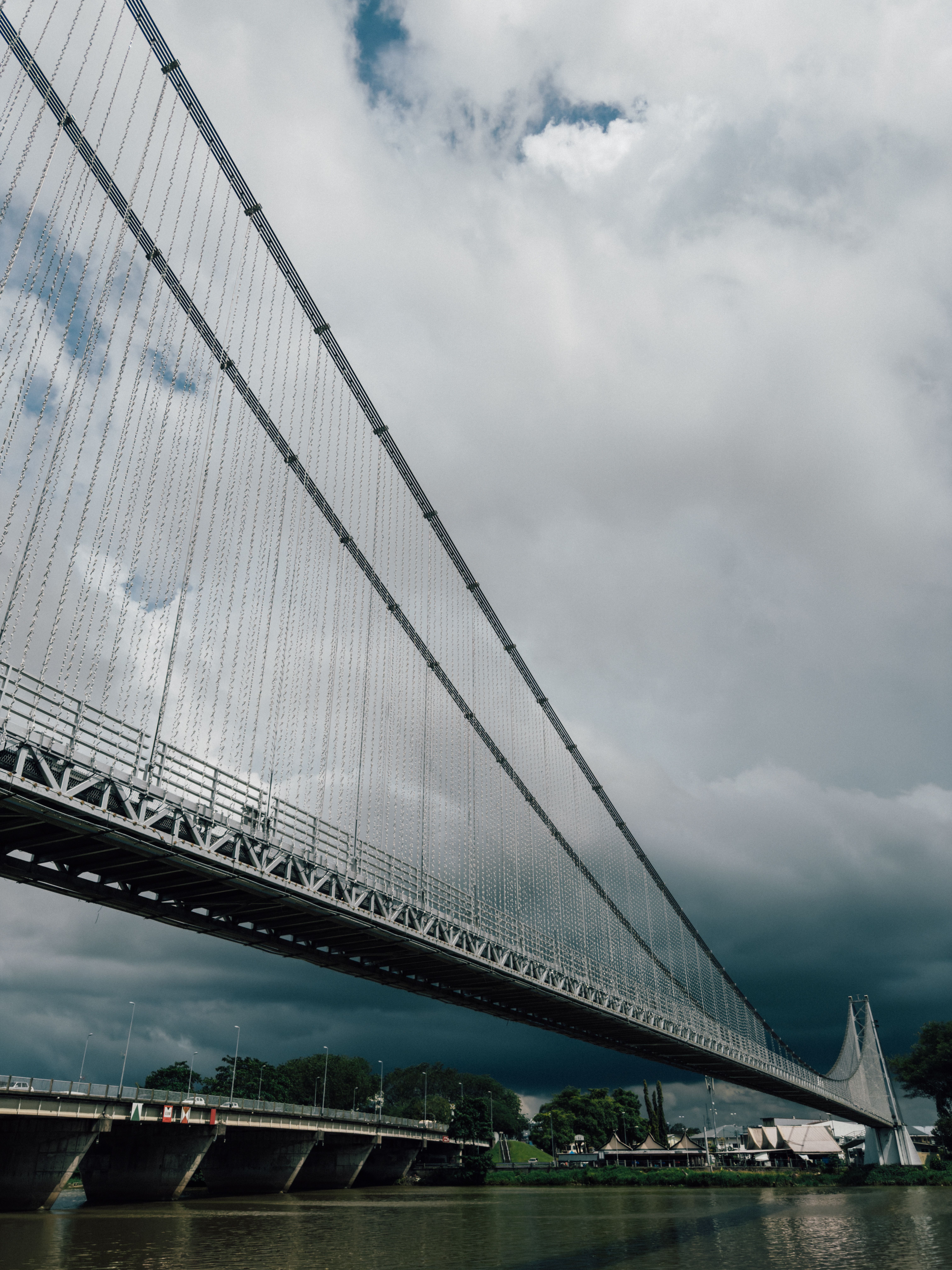 Dramatic View of Suspension Bridge Under Clouds · Free Stock Photo