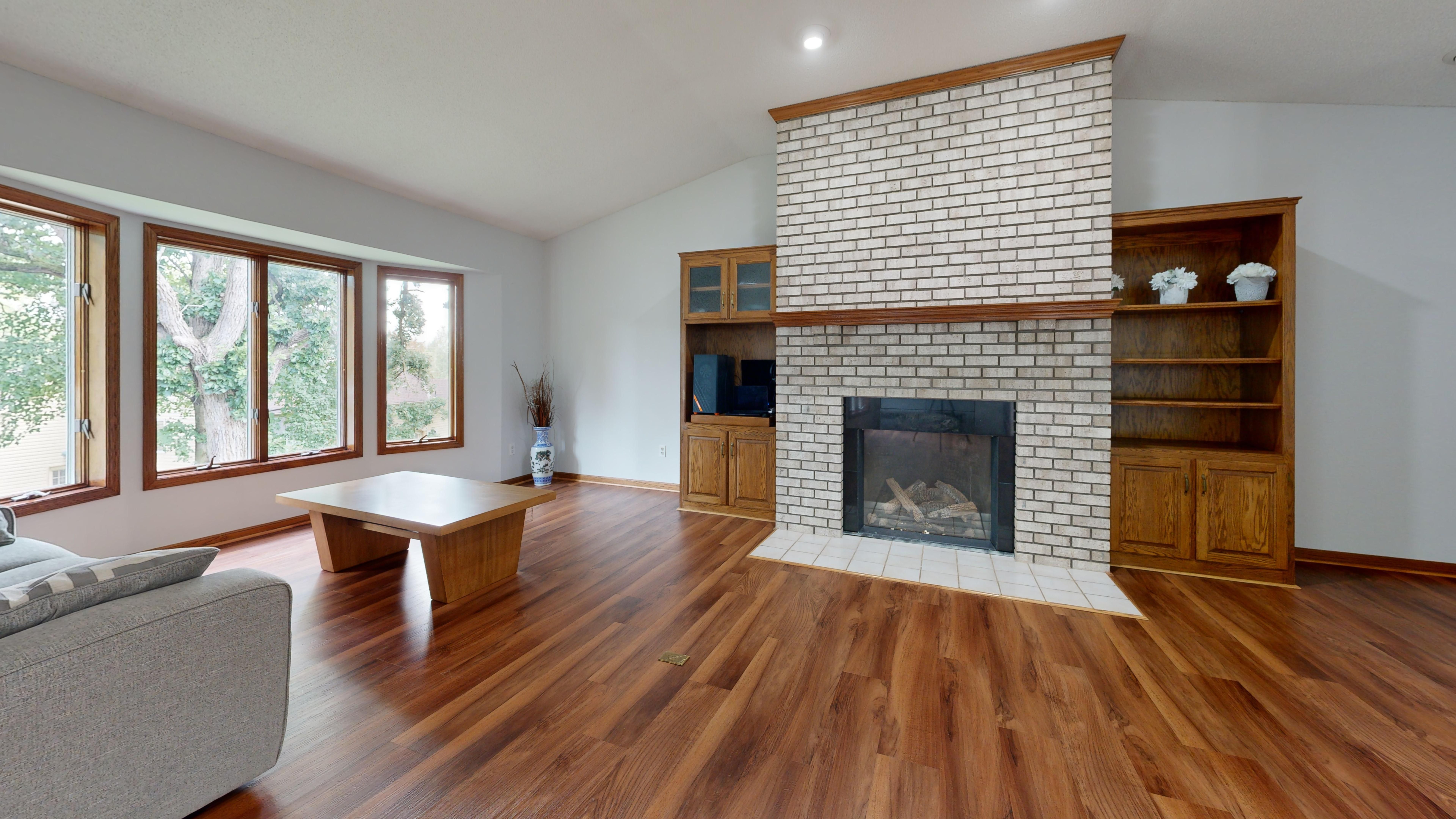 Cozy Living Room with Brick Fireplace and Large Windows · Free Stock Photo