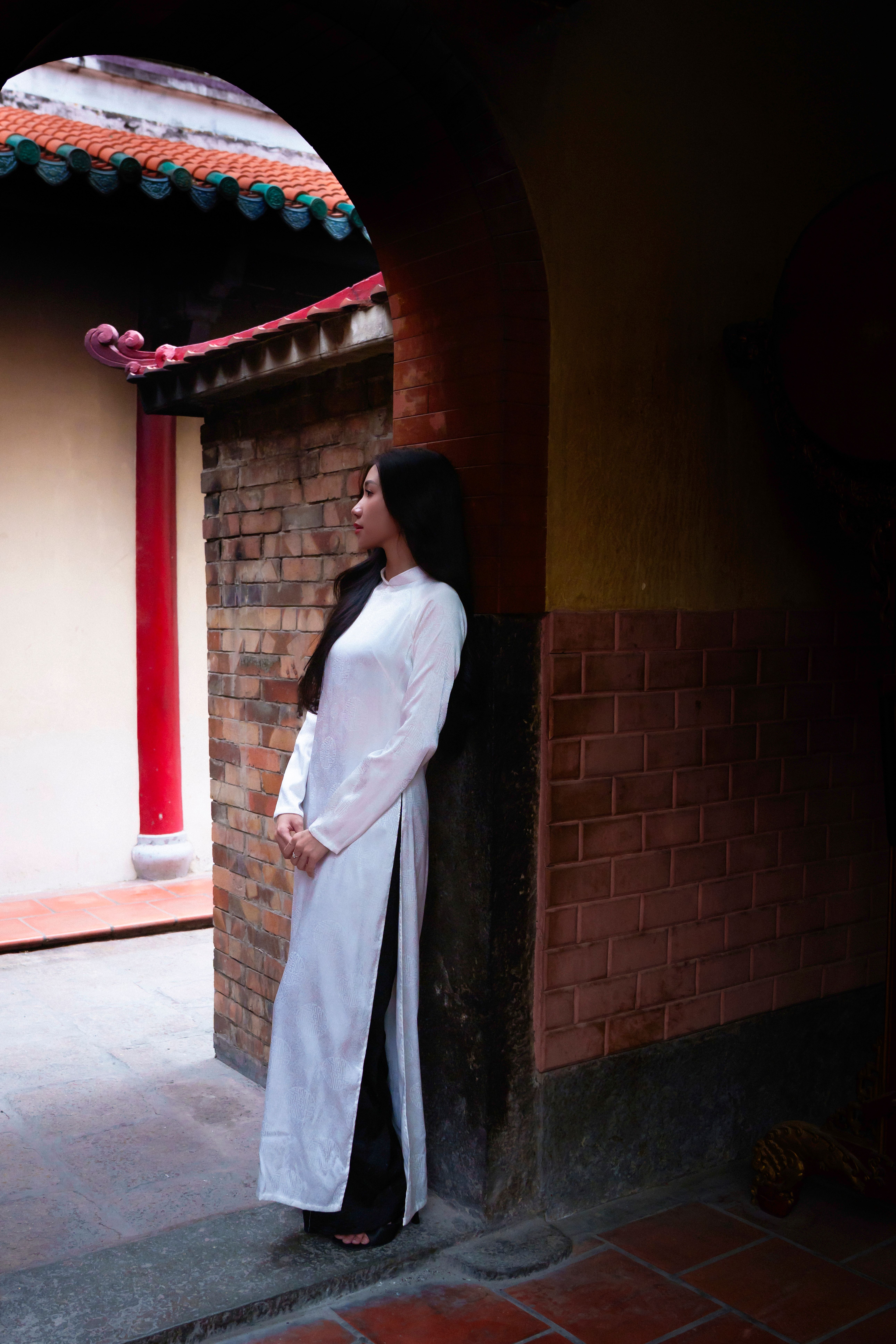 Woman in Traditional Dress Standing in Temple Archway · Free Stock Photo