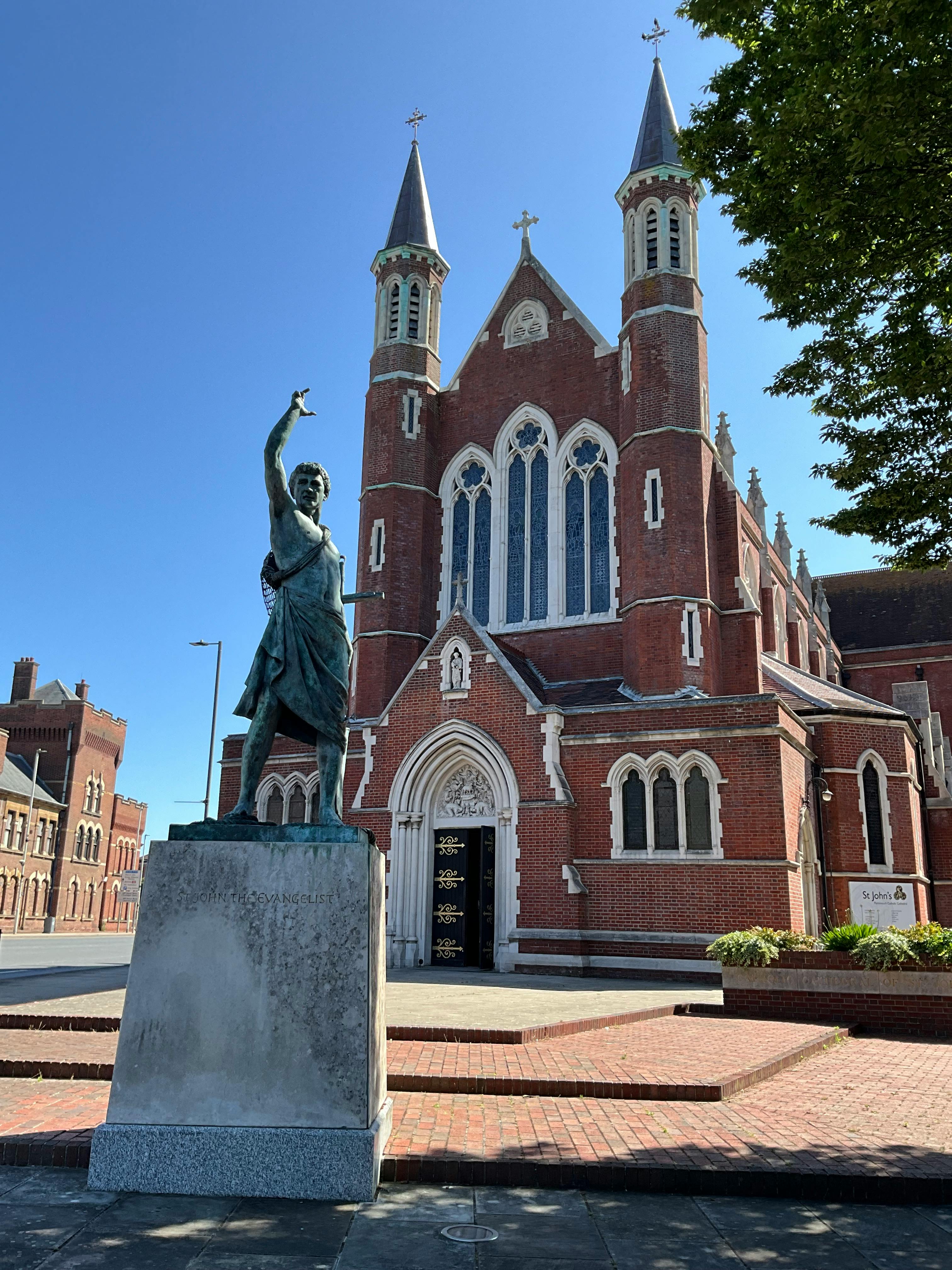 Statue in Front of Historic Red Brick Church · Free Stock Photo