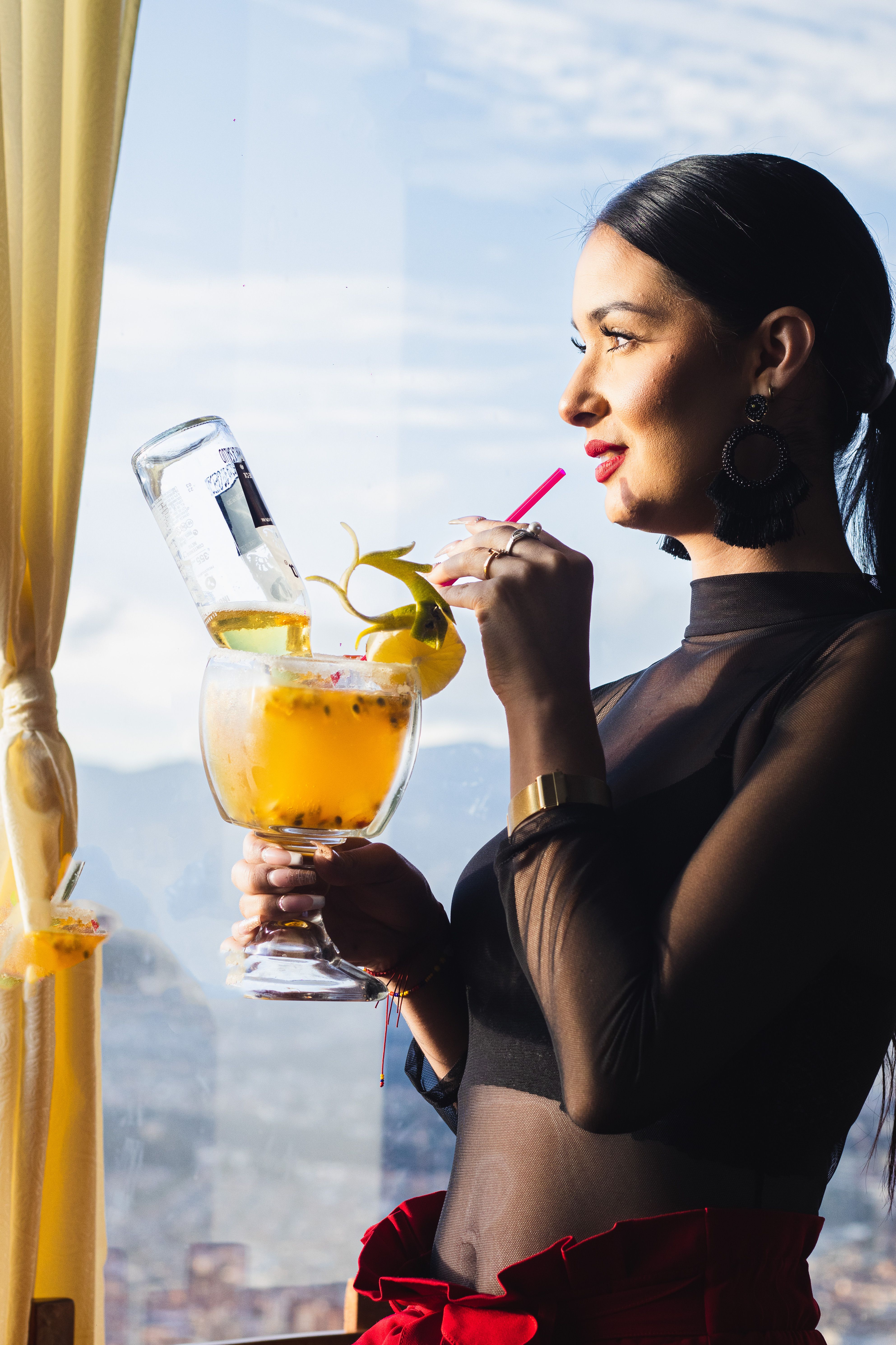Woman Enjoying a Large Cocktail by a Window · Free Stock Photo