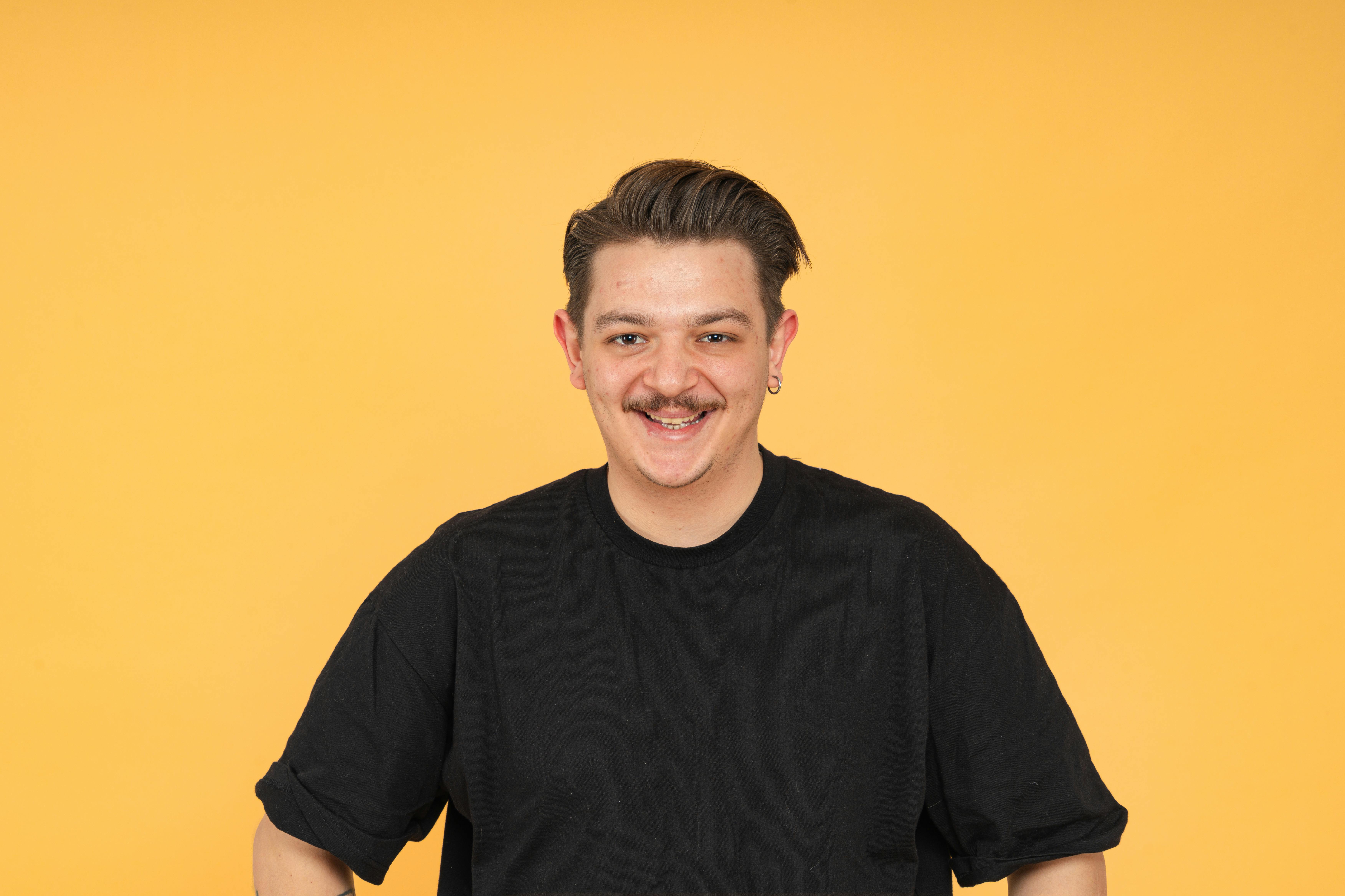 Pria Tersenyum Dengan Latar Belakang Studio Berwarna Kuning Cerah · Foto Stok Gratis