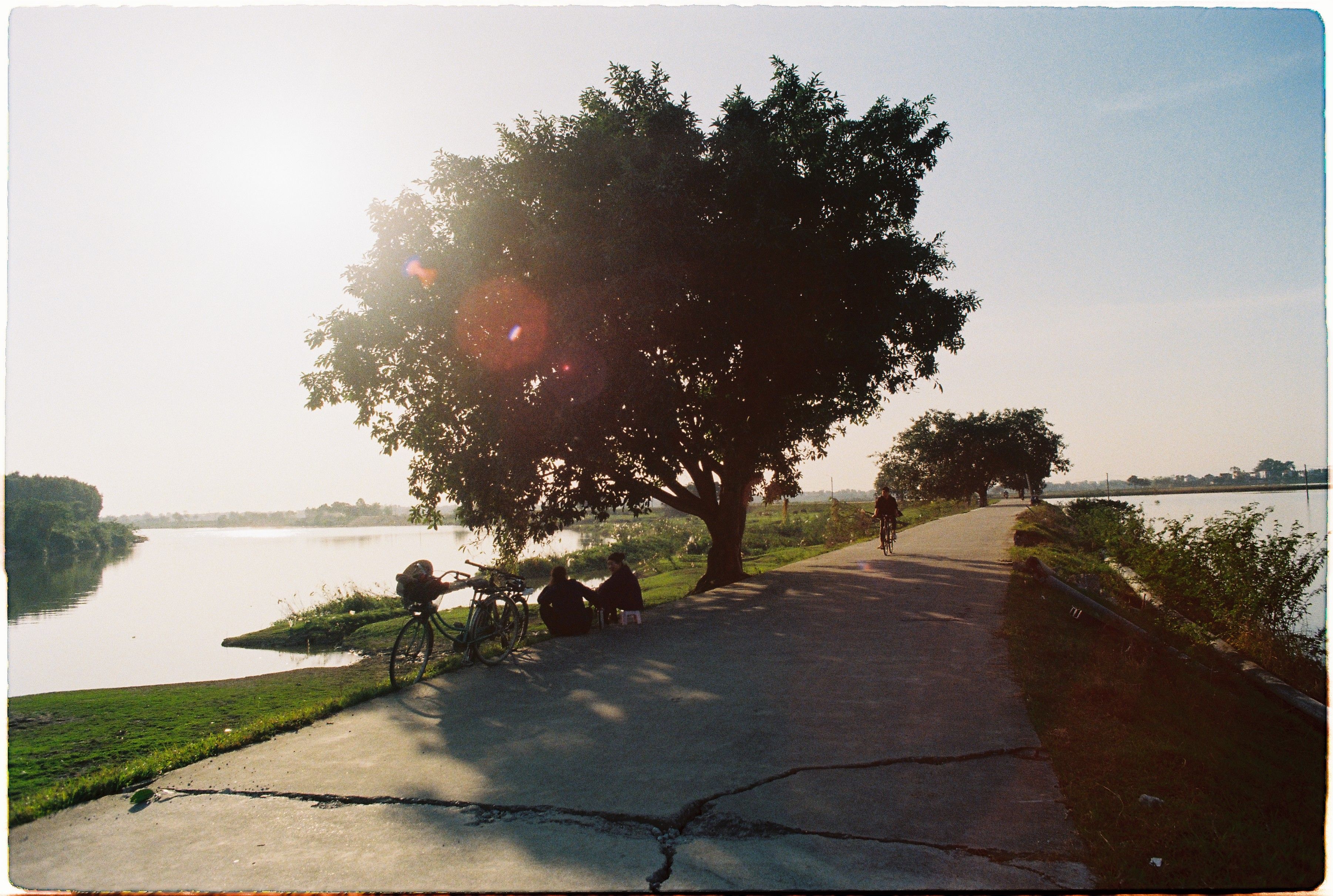 Serene Riverside Path with People and Bicycles · Free Stock Photo