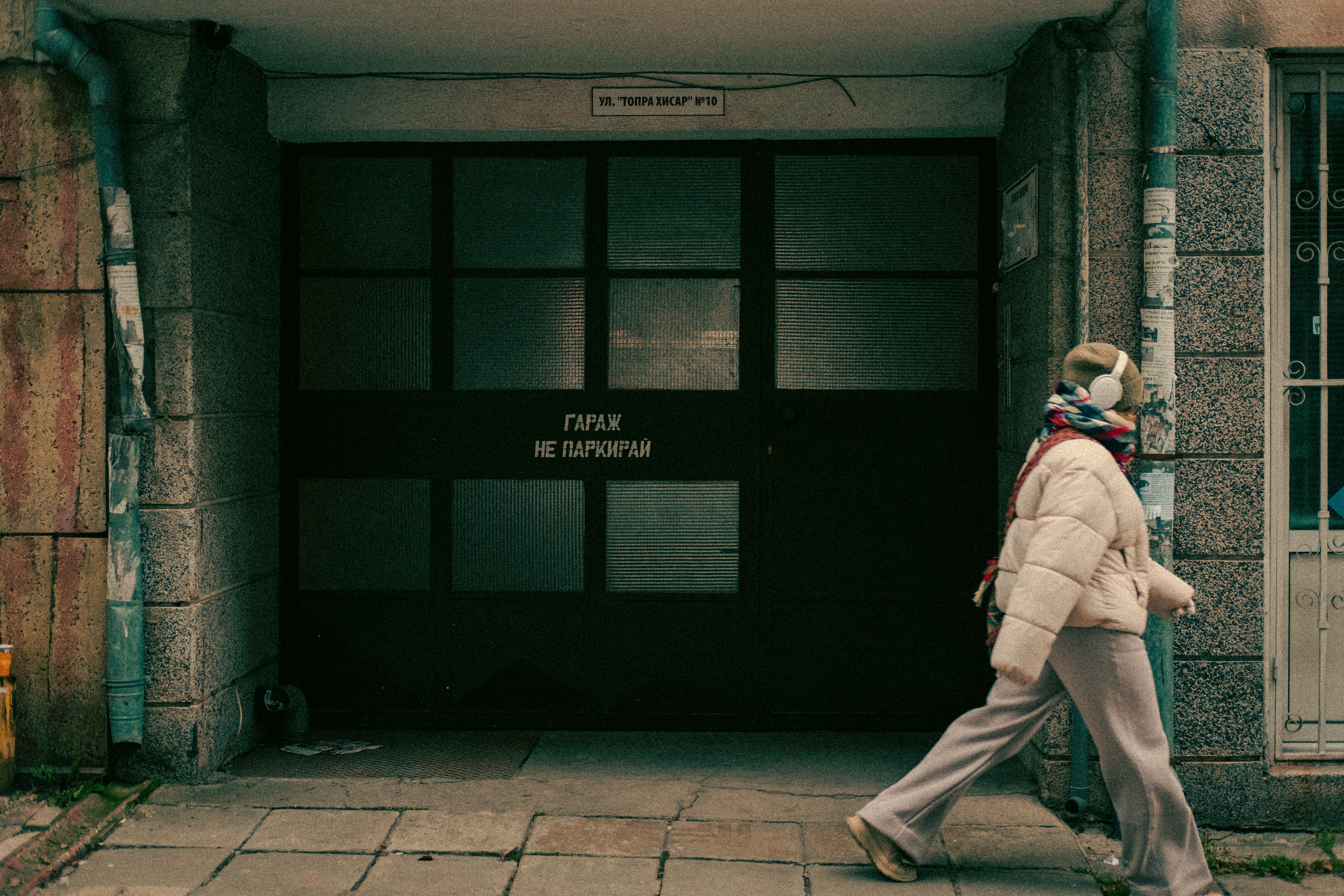 Woman Walking by Urban Garage with Sign · Free Stock Photo