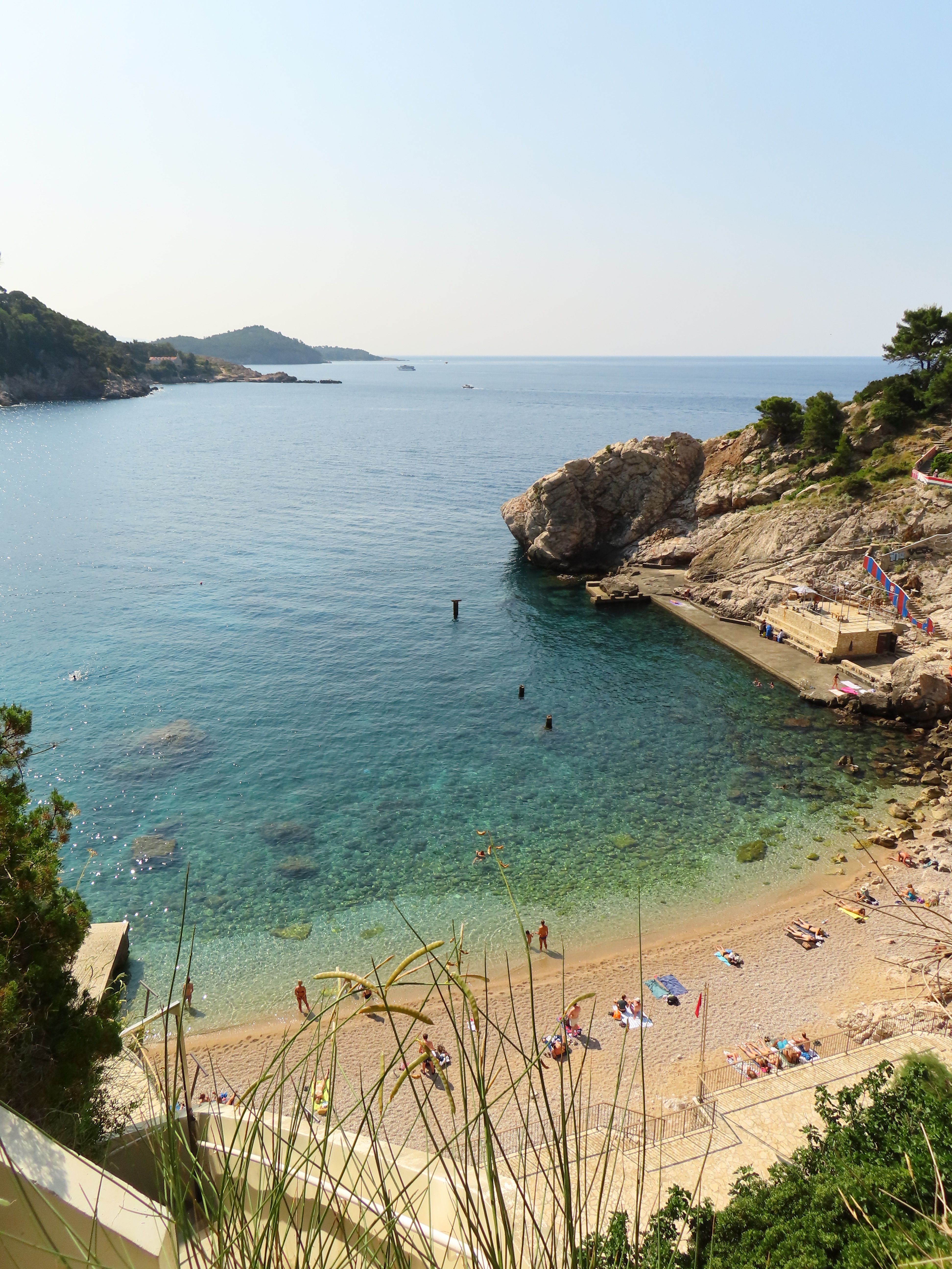 Scenic Mediterranean Beach Cove with Swimmers · Free Stock Photo