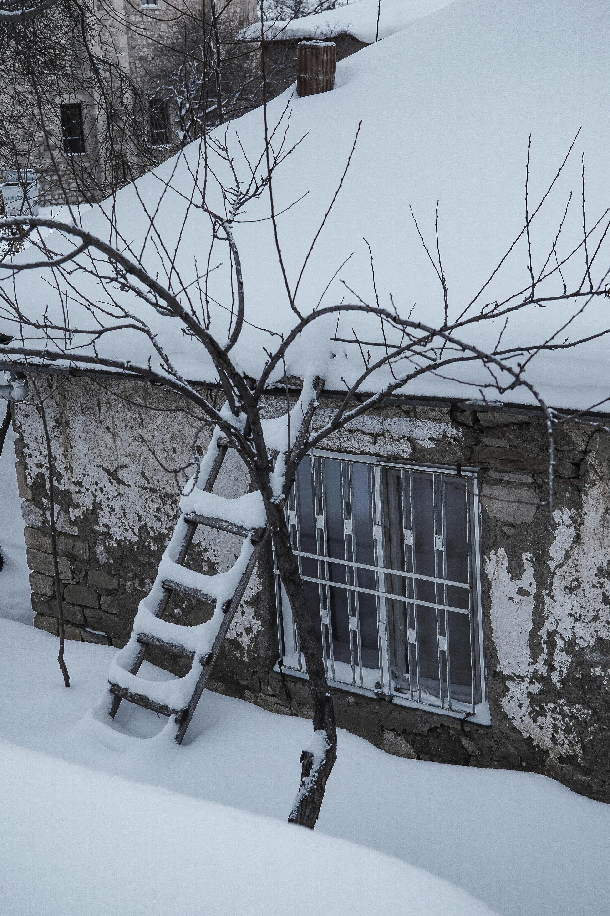 Snow-Covered Winter Scene with Ladder and Old Building · Free Stock Photo