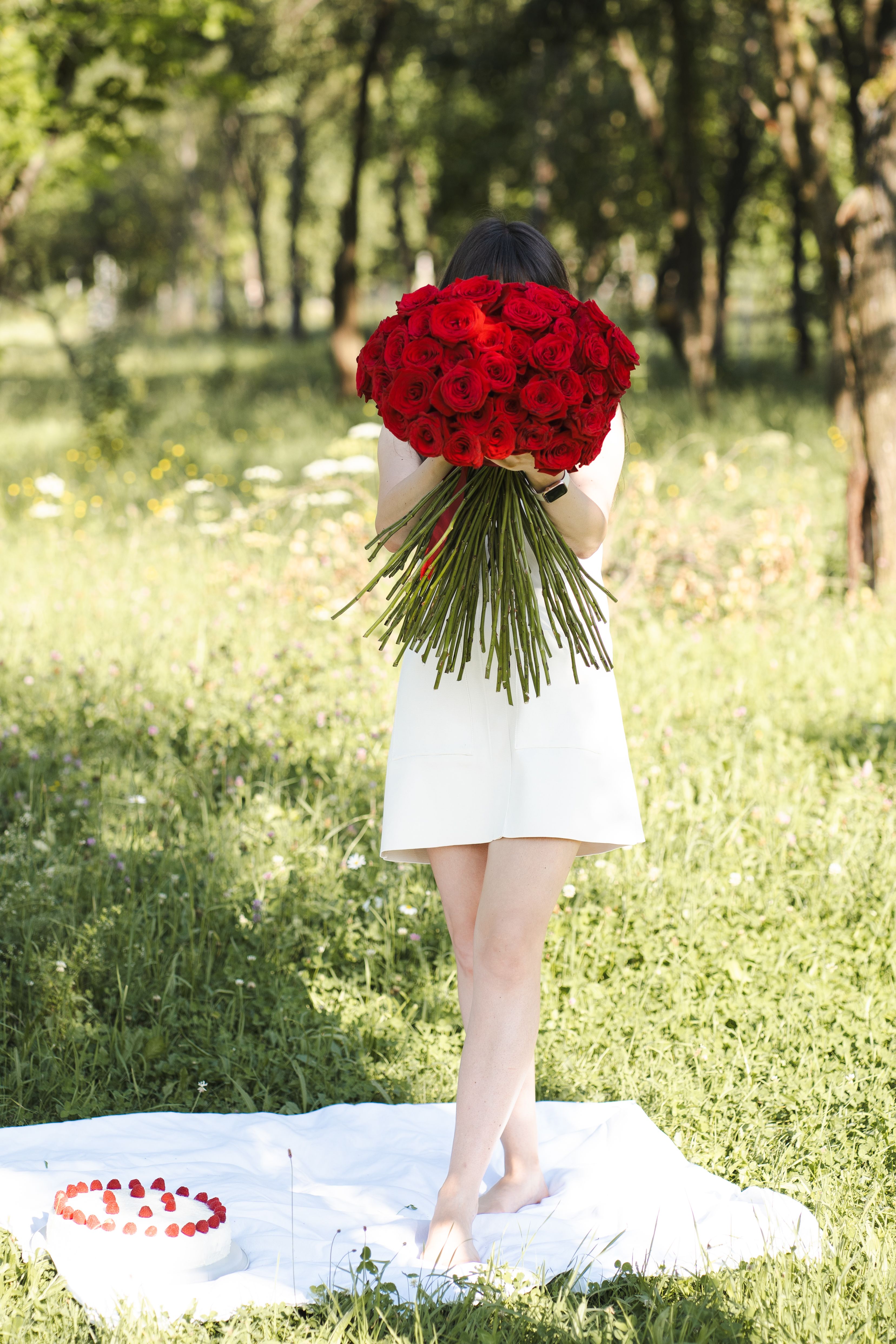 Woman Hiding Behind Bouquet of Red Roses Outdoors · Free Stock Photo
