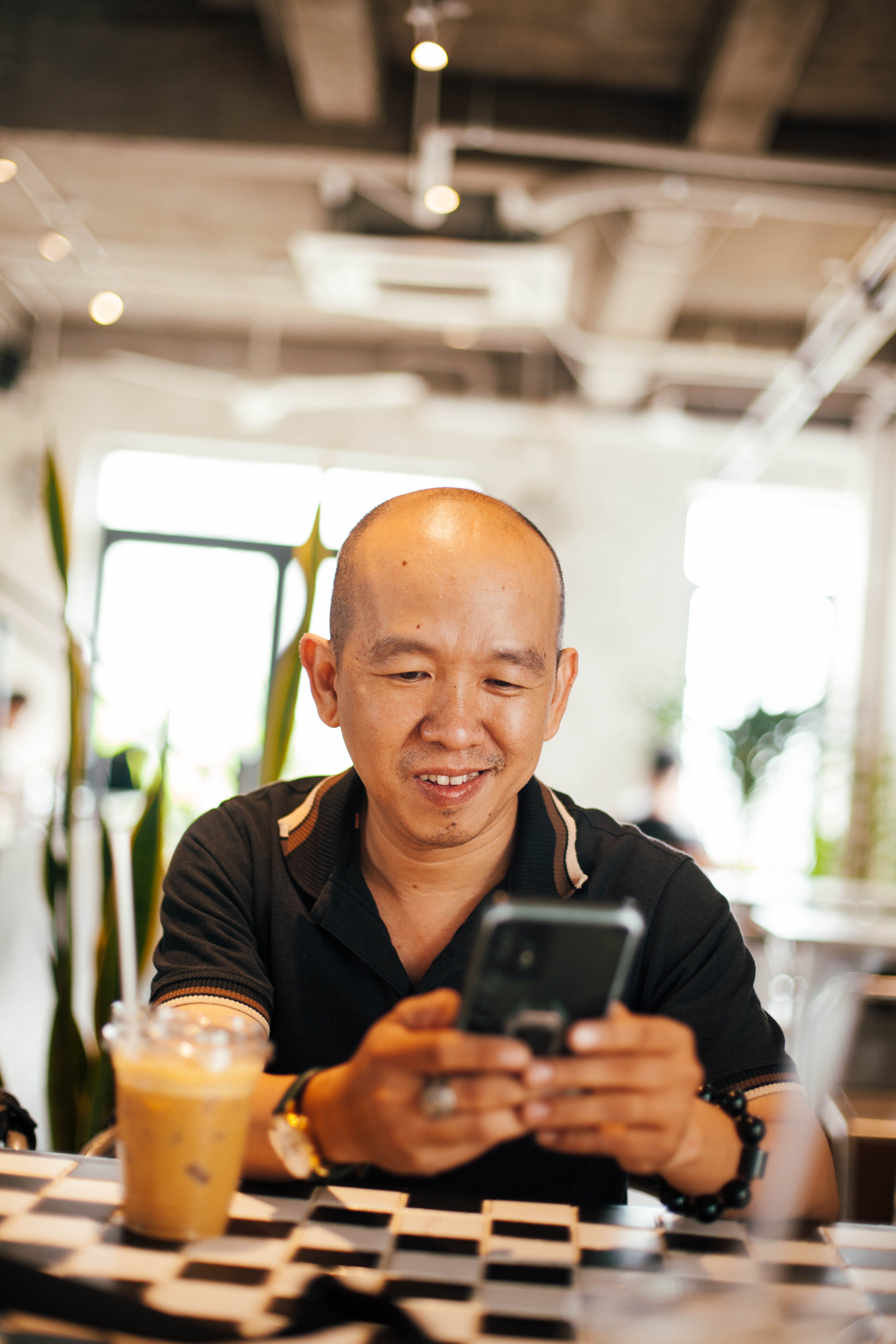 Smiling man enjoying iced coffee in a modern cafe · Free Stock Photo
