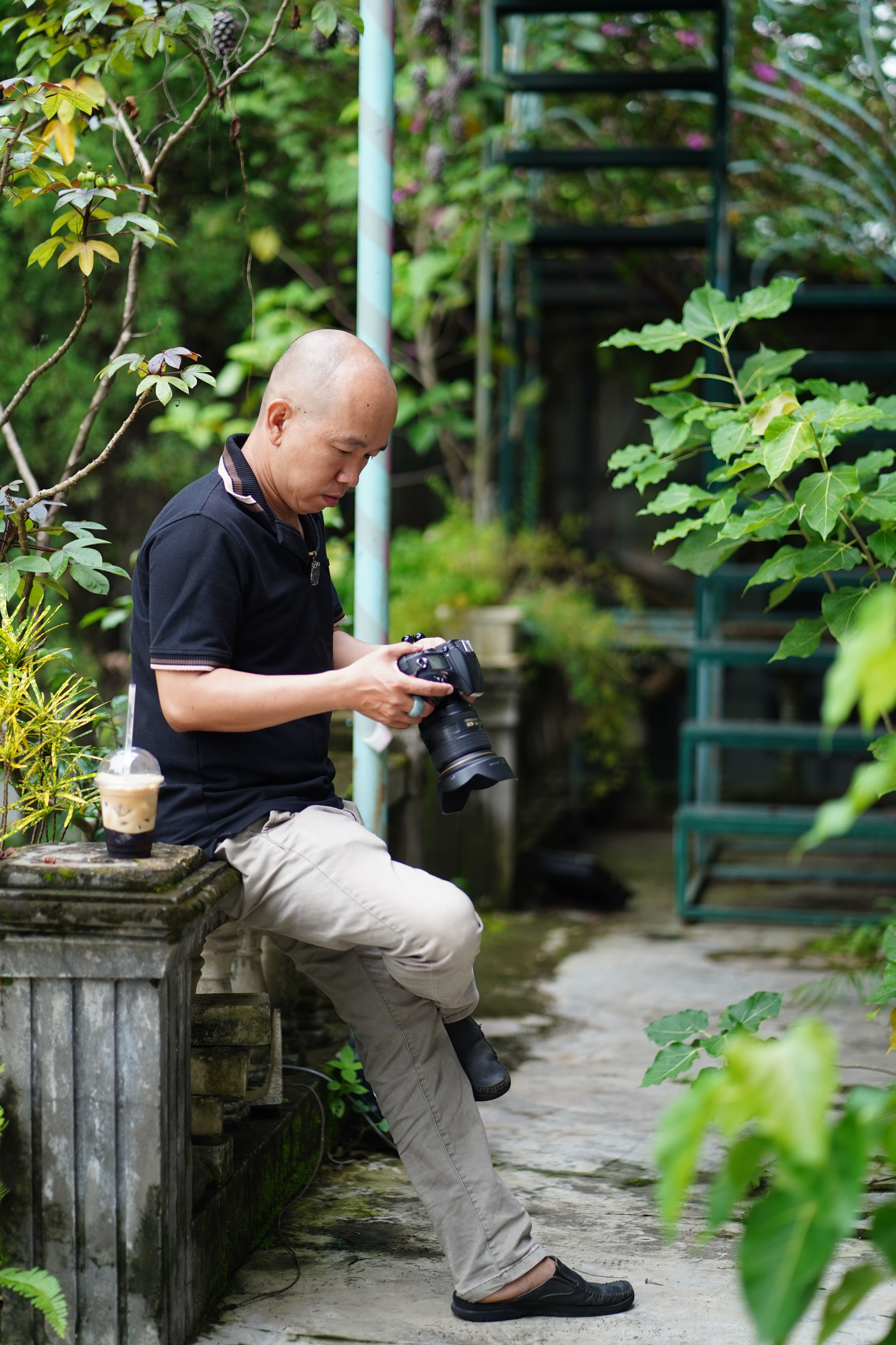 Photographer Reviewing Camera in Lush Garden Setting · Free Stock Photo