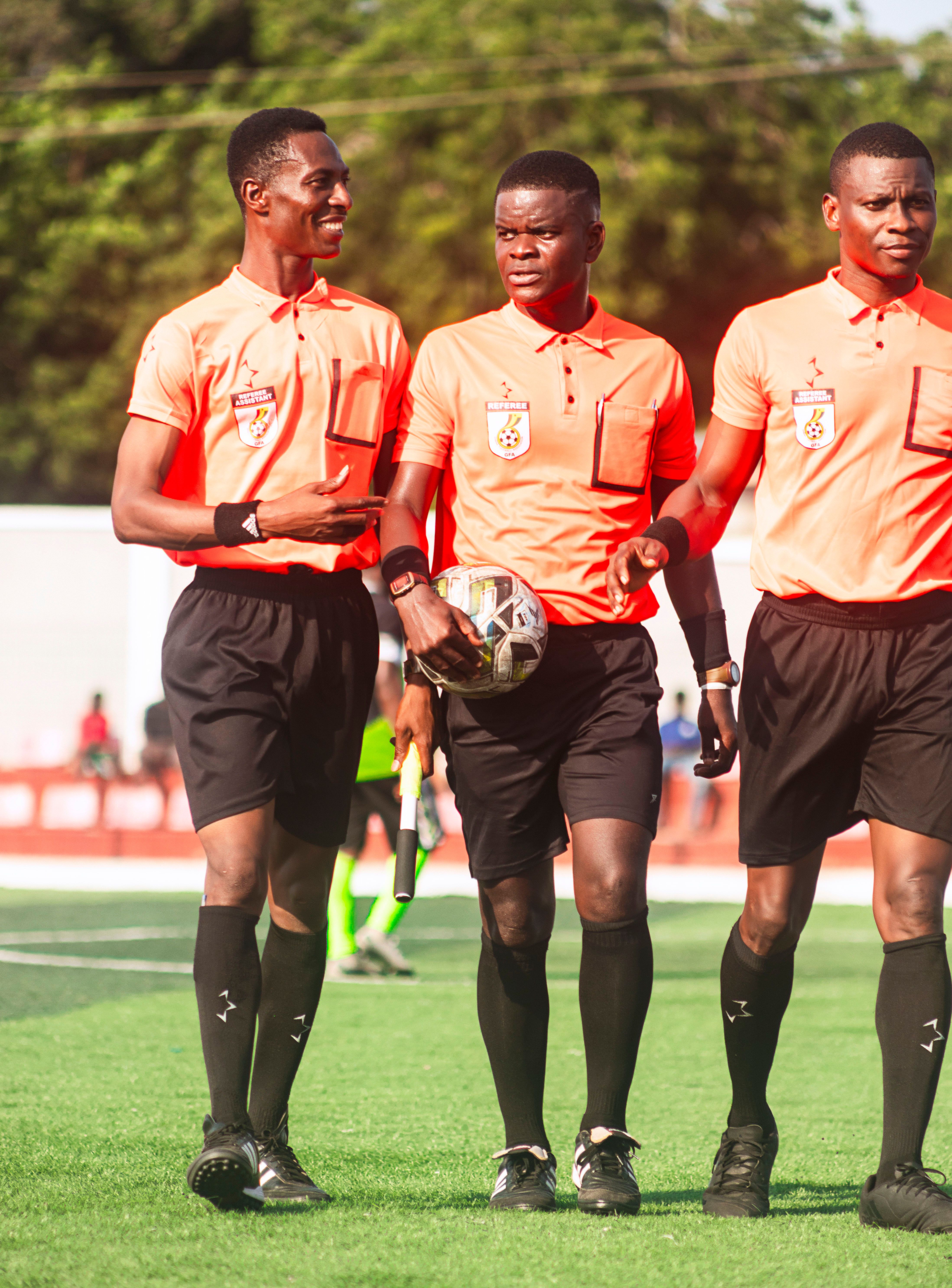 Soccer Referees in Orange Uniforms on a Field · Free Stock Photo