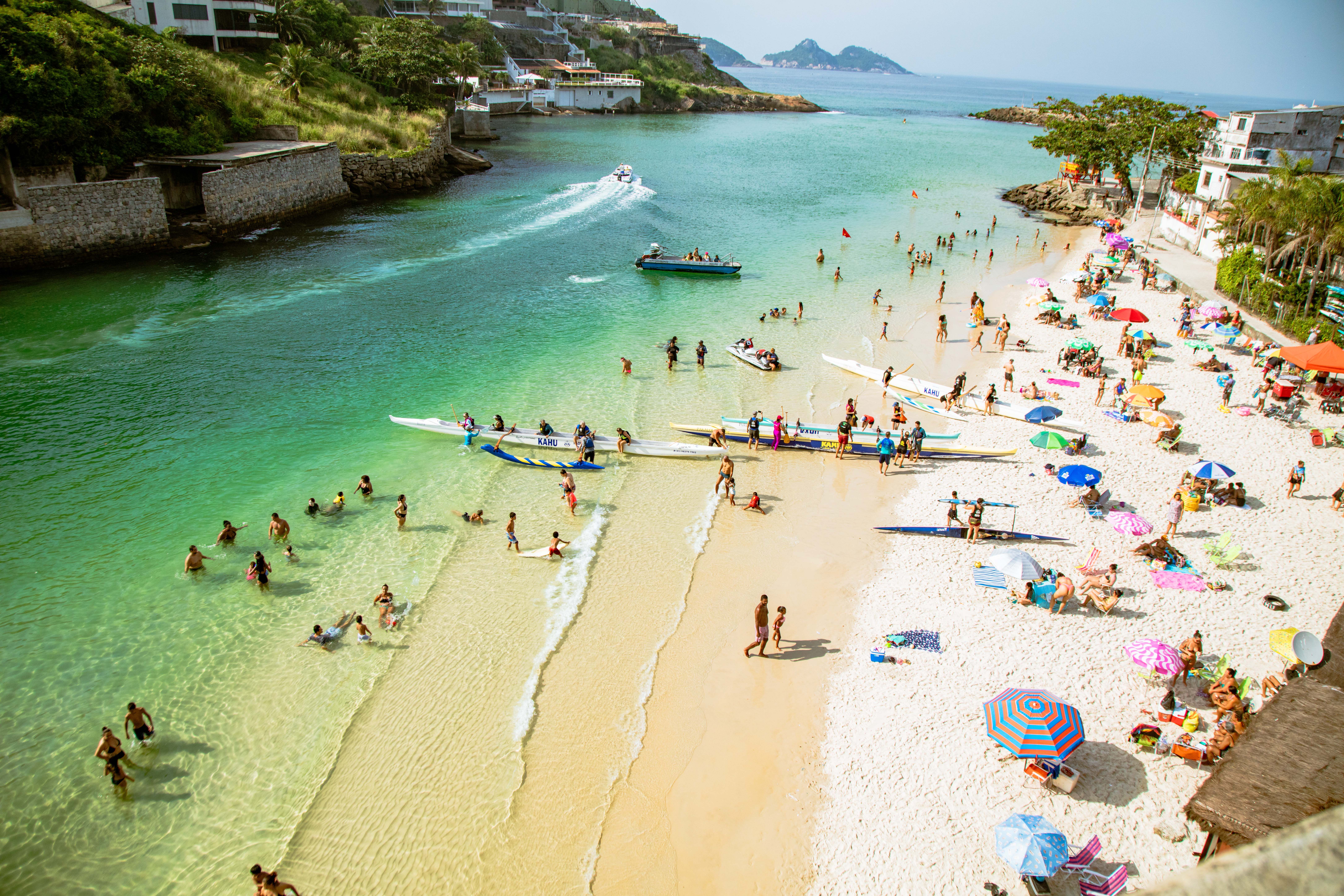 Vibrant Beach Scene with Sunbathers and Boats · Free Stock Photo