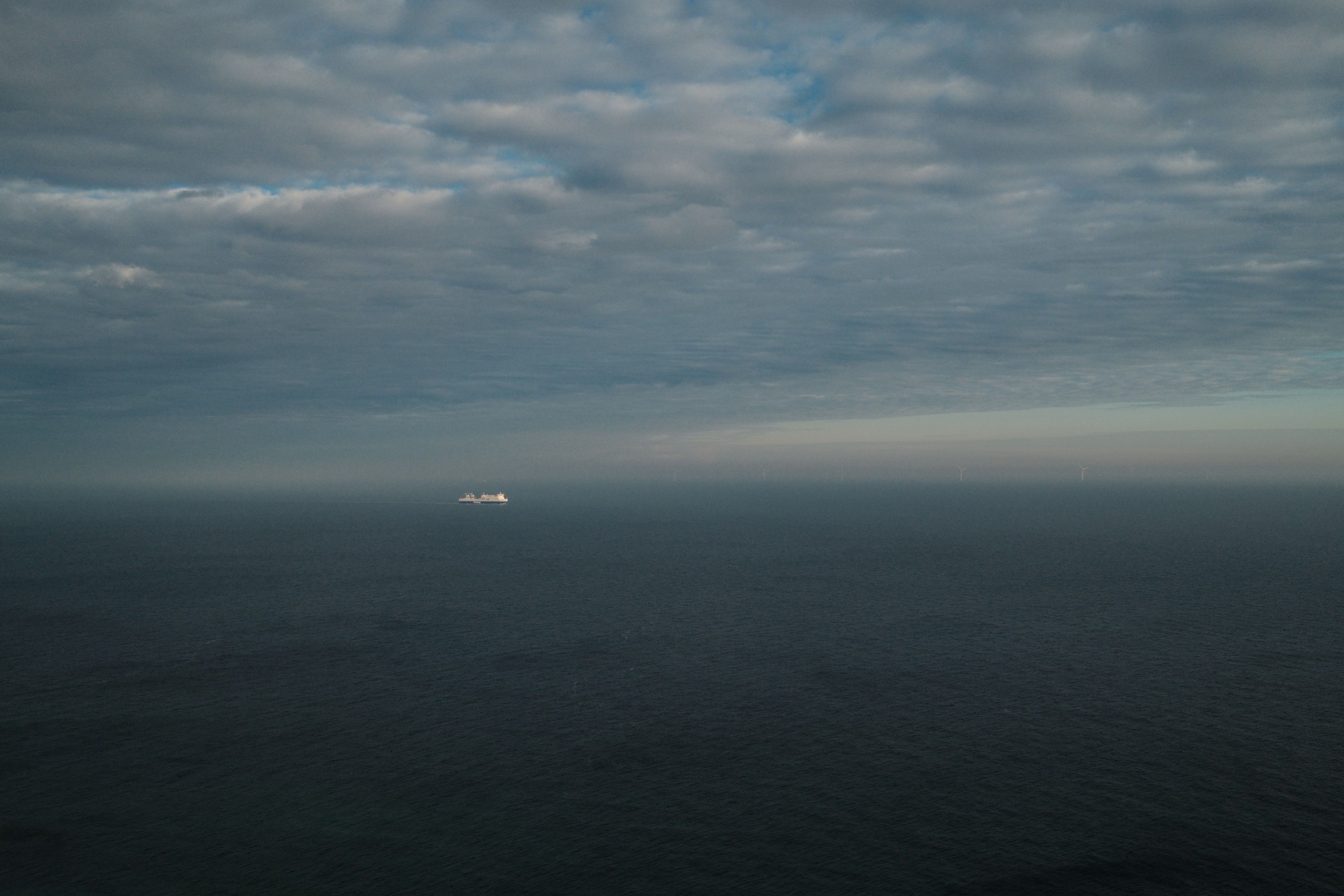 Vast Ocean with Distant Ship Under Cloudy Sky · Free Stock Photo