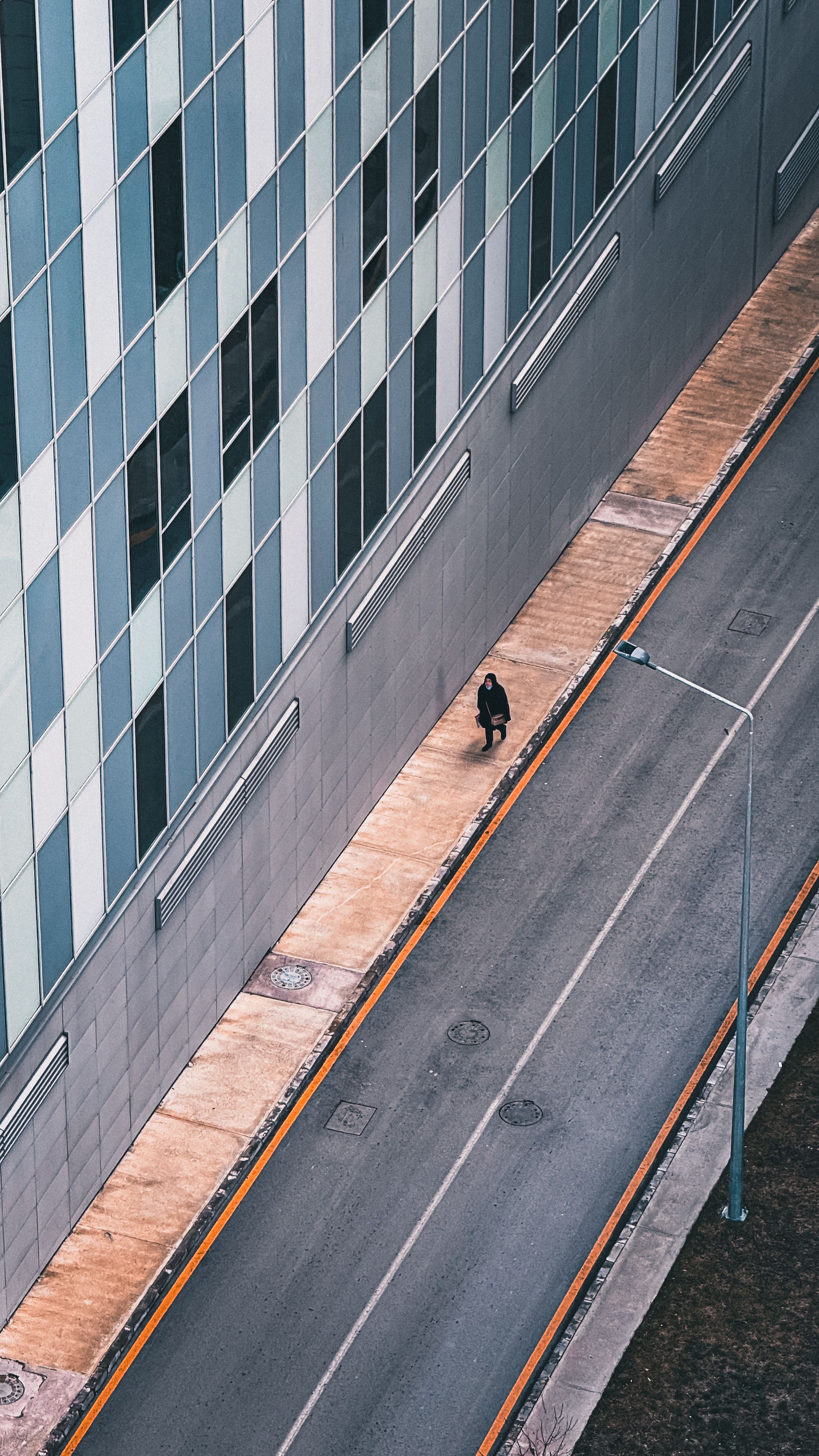 Aerial view of solitary figure walking by urban building · Free Stock Photo