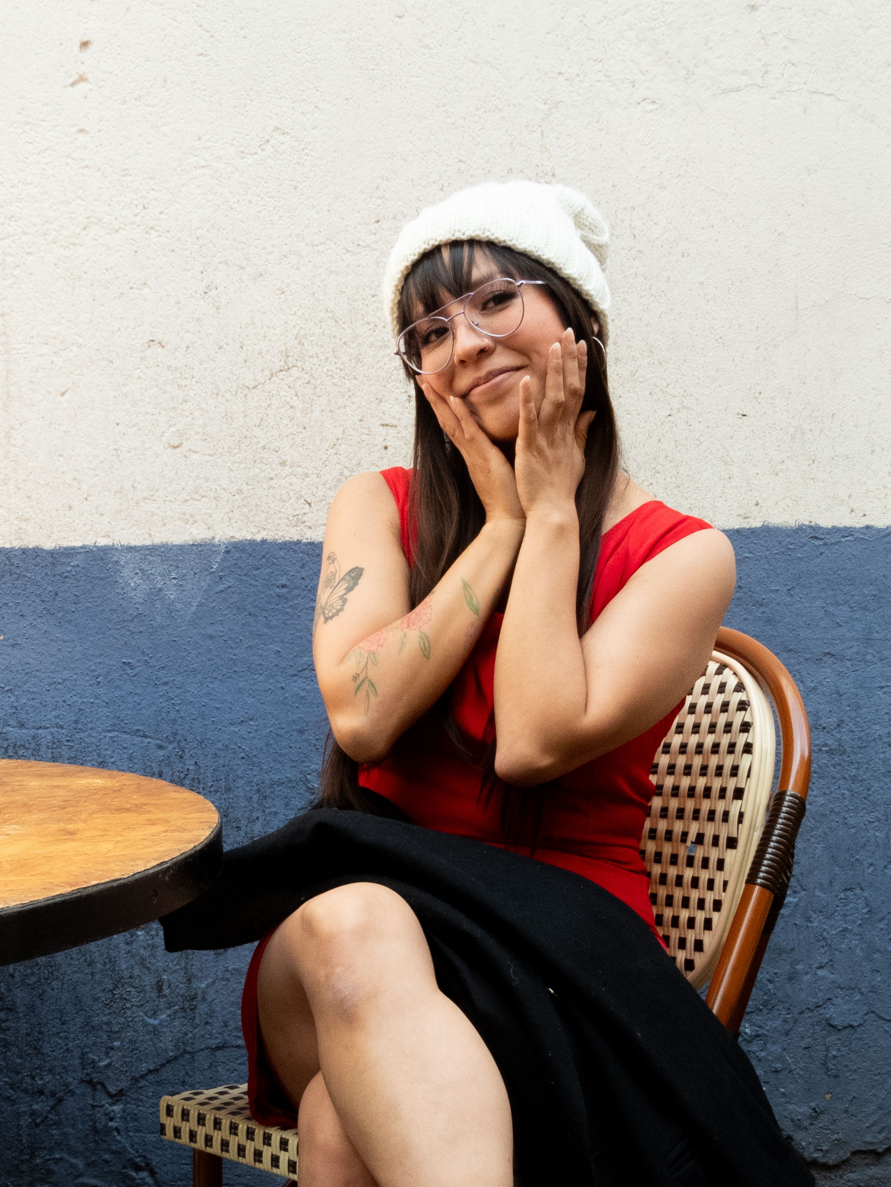 Woman in Red Dress Seated with Playful Expression · Free Stock Photo
