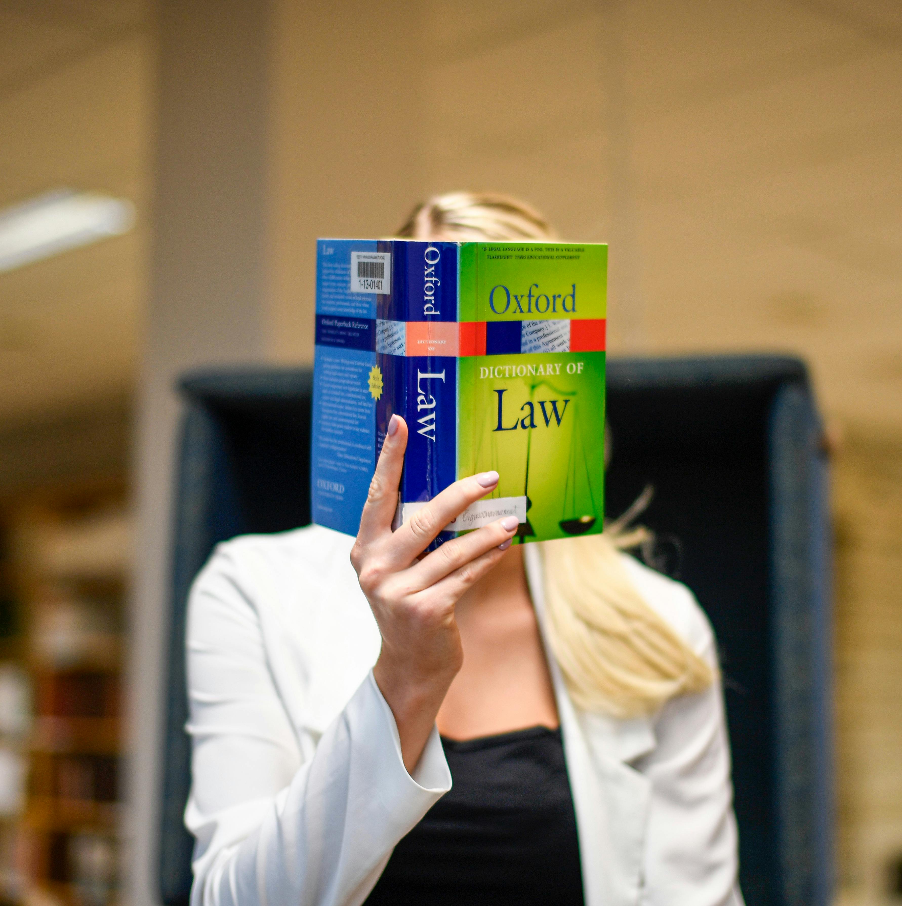 Young Woman Reading Oxford Law Dictionary in Library · Free Stock Photo