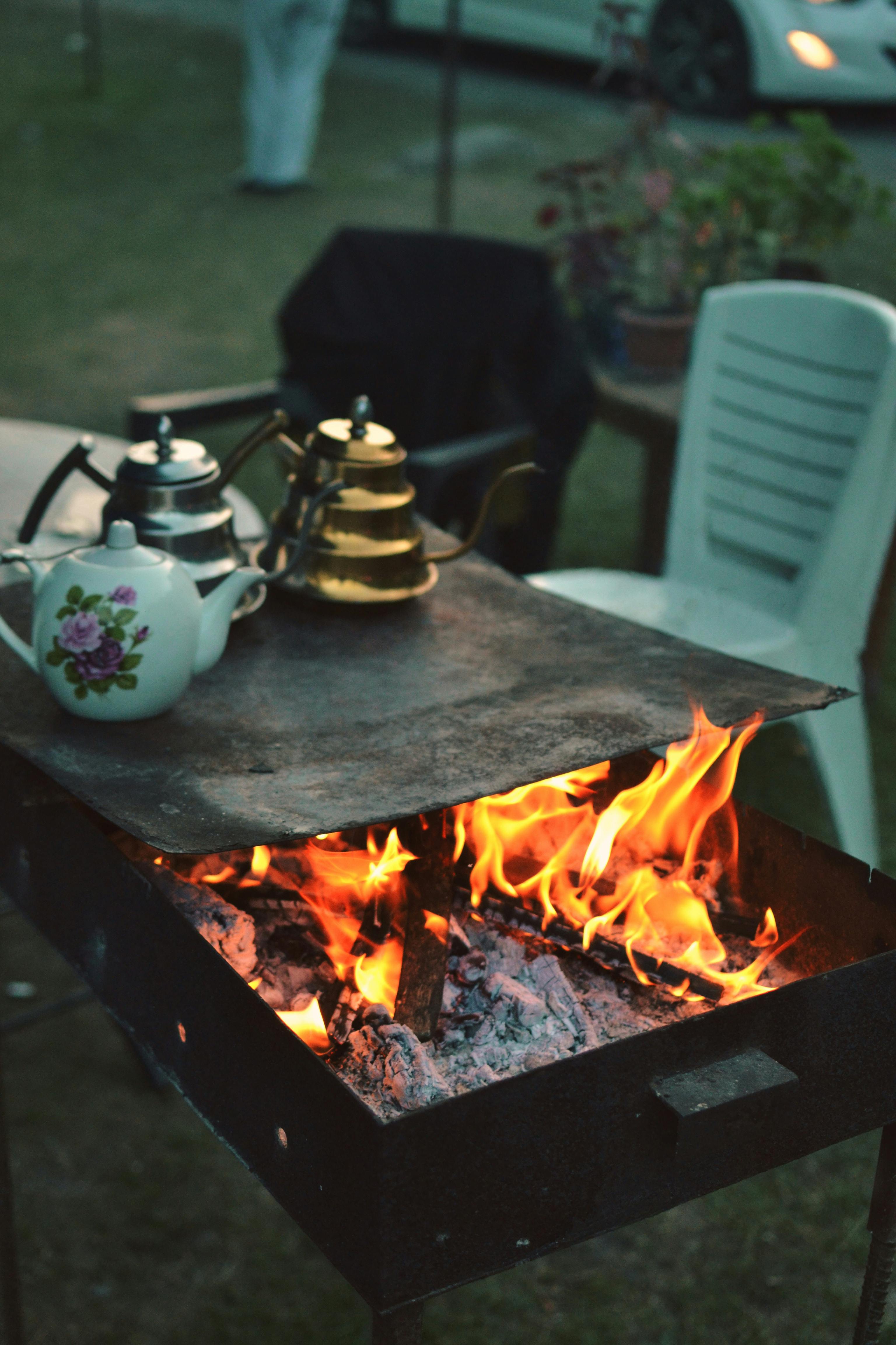 Cozy Outdoor Campfire with Teapots on Metal Plate · Free Stock Photo