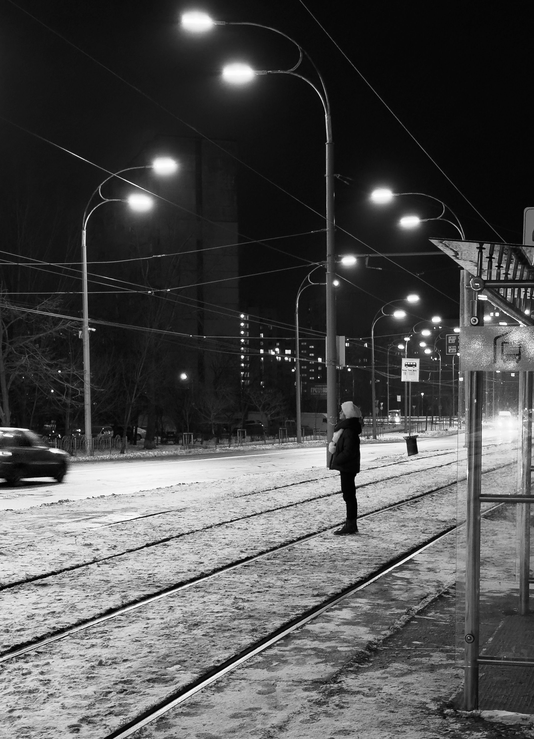 Solitude at Night: Person Waiting by Snowy Tram Tracks · Free Stock Photo
