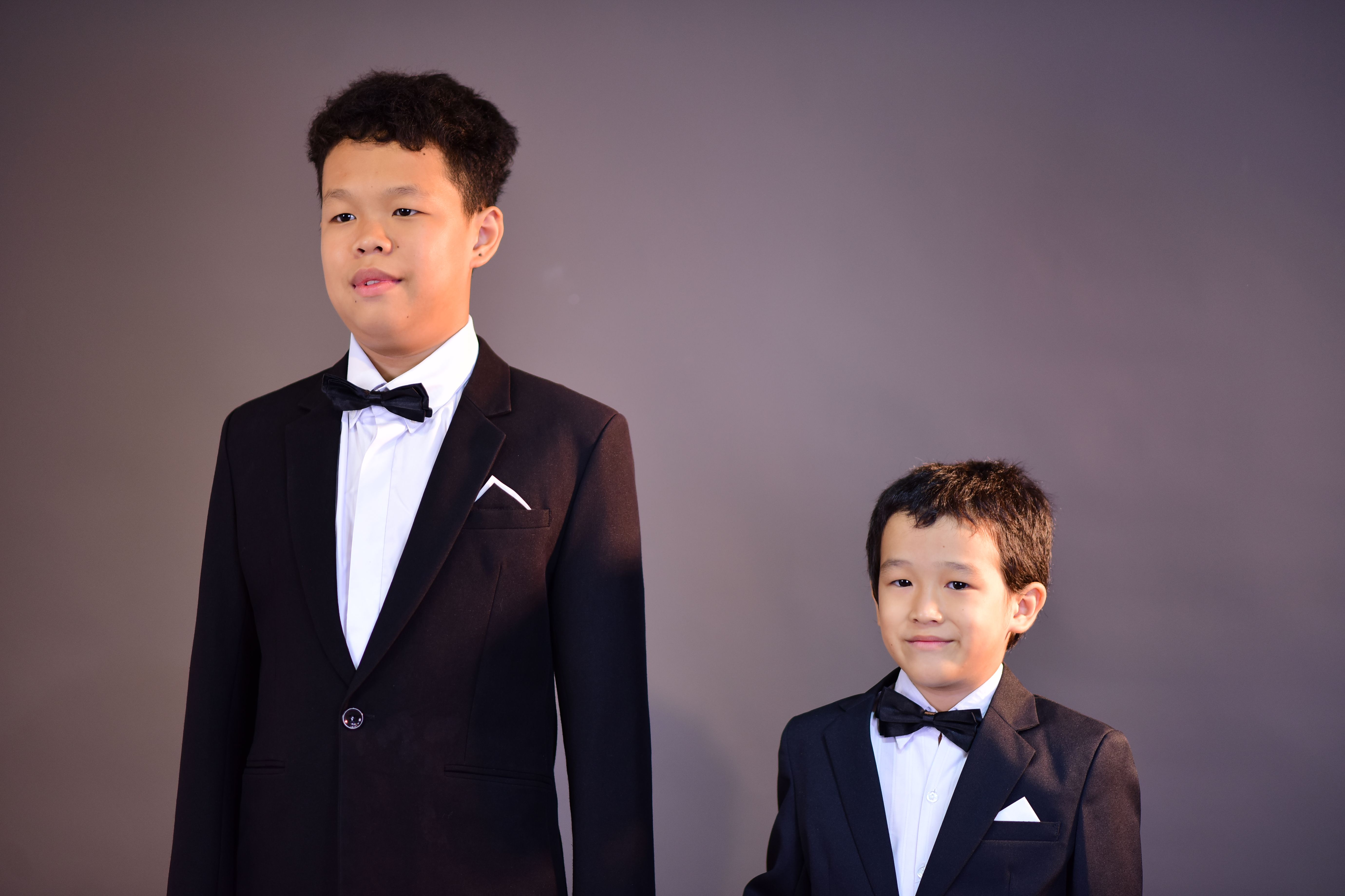 Two Young Boys in Formal Attire Against Gray Background · Free Stock Photo