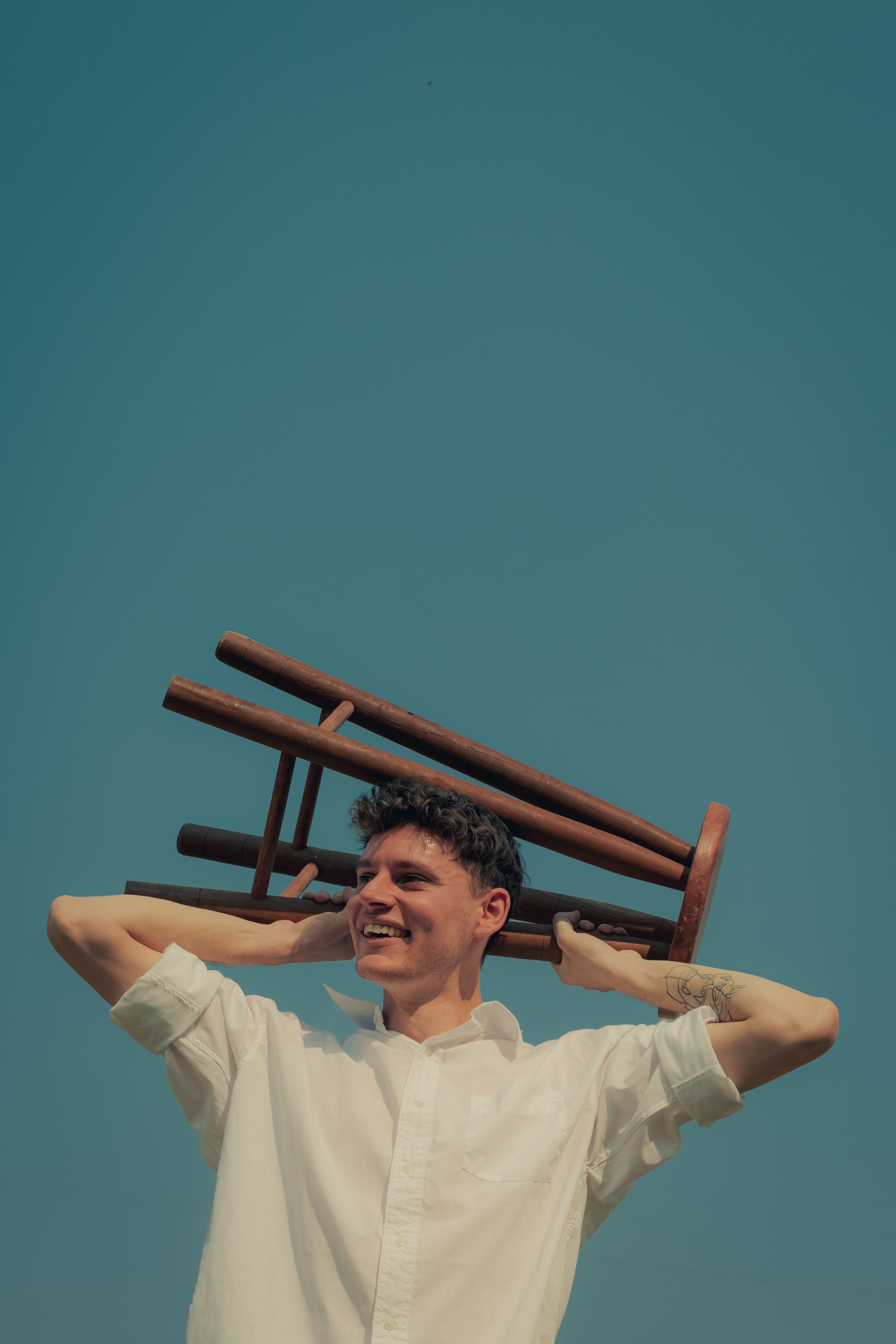 Man Carrying Wooden Chair Outdoors · Free Stock Photo