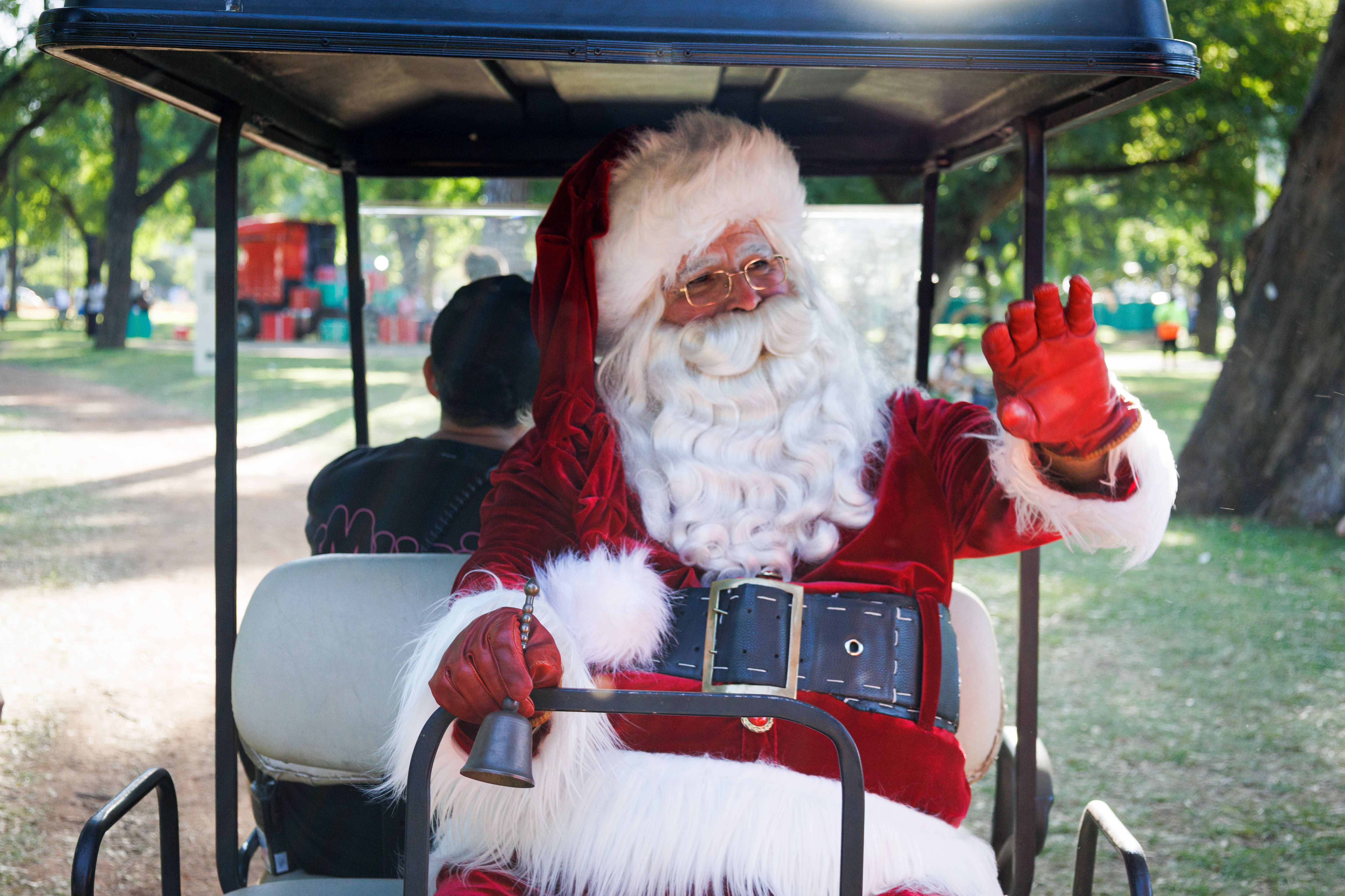 Santa Claus Waving from a Golf Cart in Park Setting · Free Stock Photo