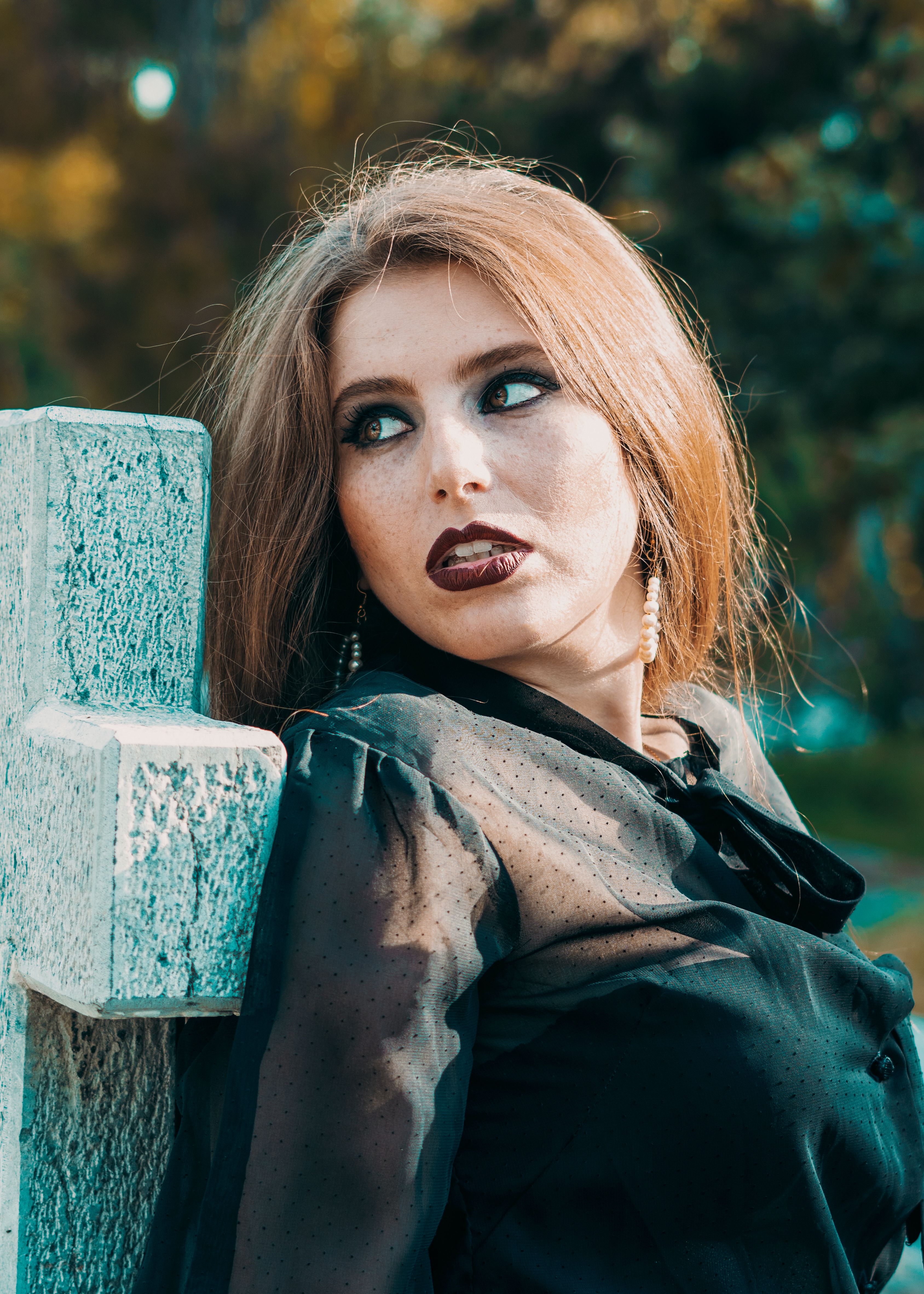 Confident woman woman leaning tombstone in cemetery · Free Stock Photo
