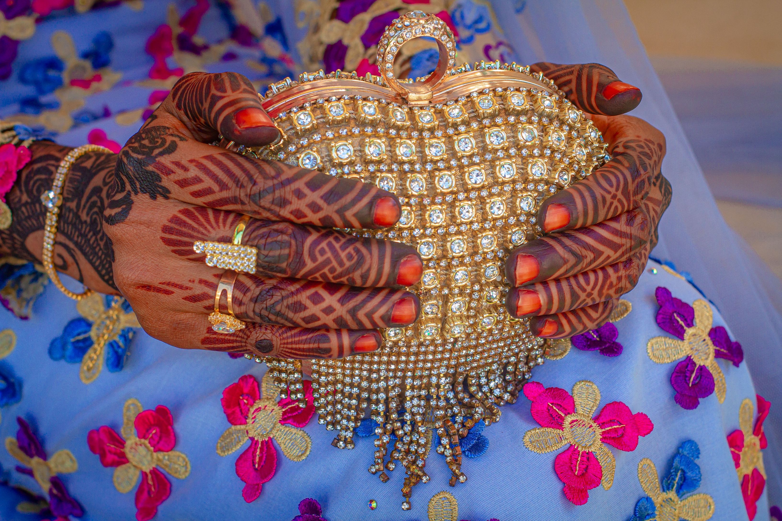 Elegant Henna Hands Holding Ornate Clutch · Free Stock Photo