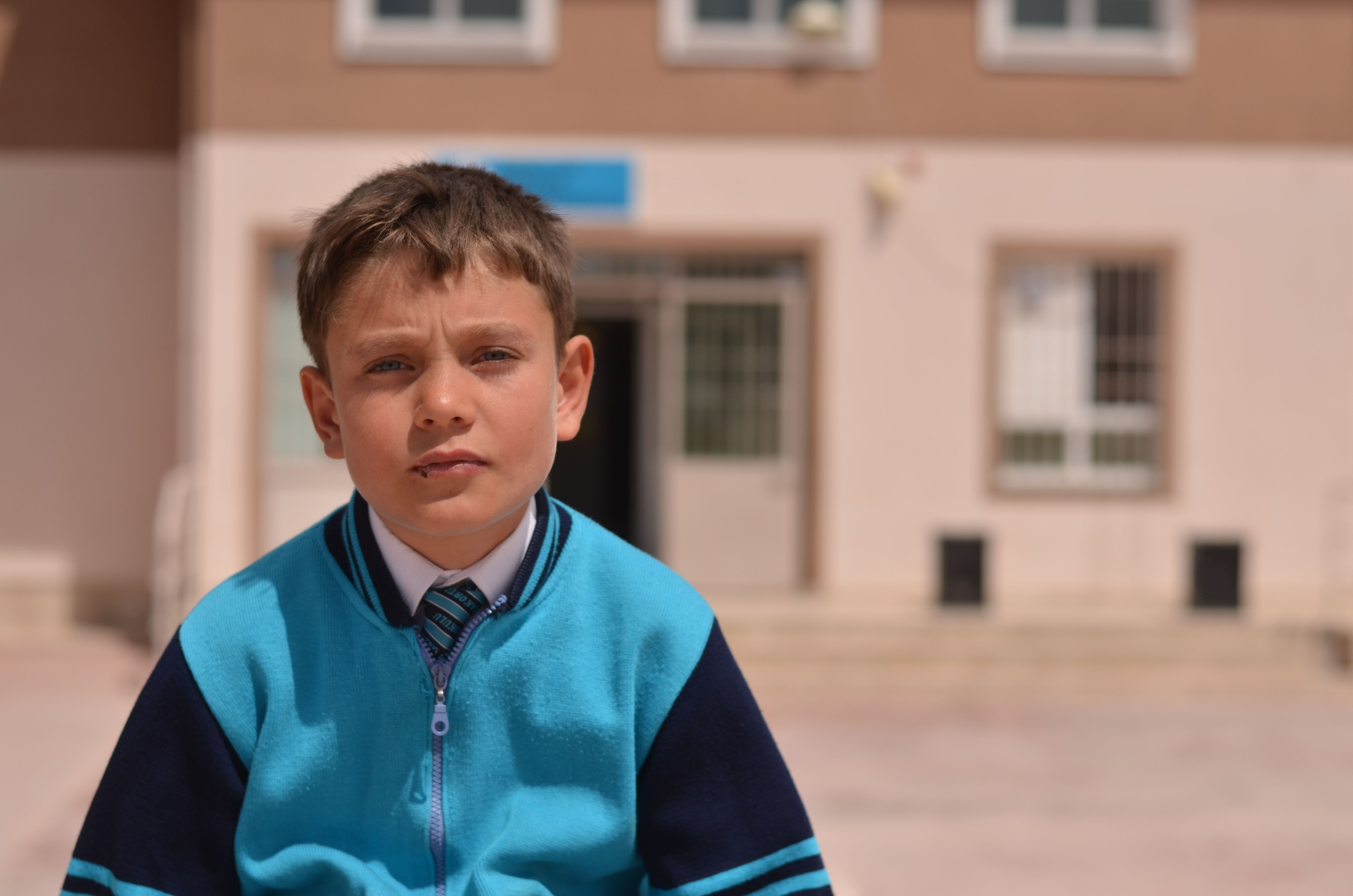 Young Boy in Blue Jacket Outside School · Free Stock Photo