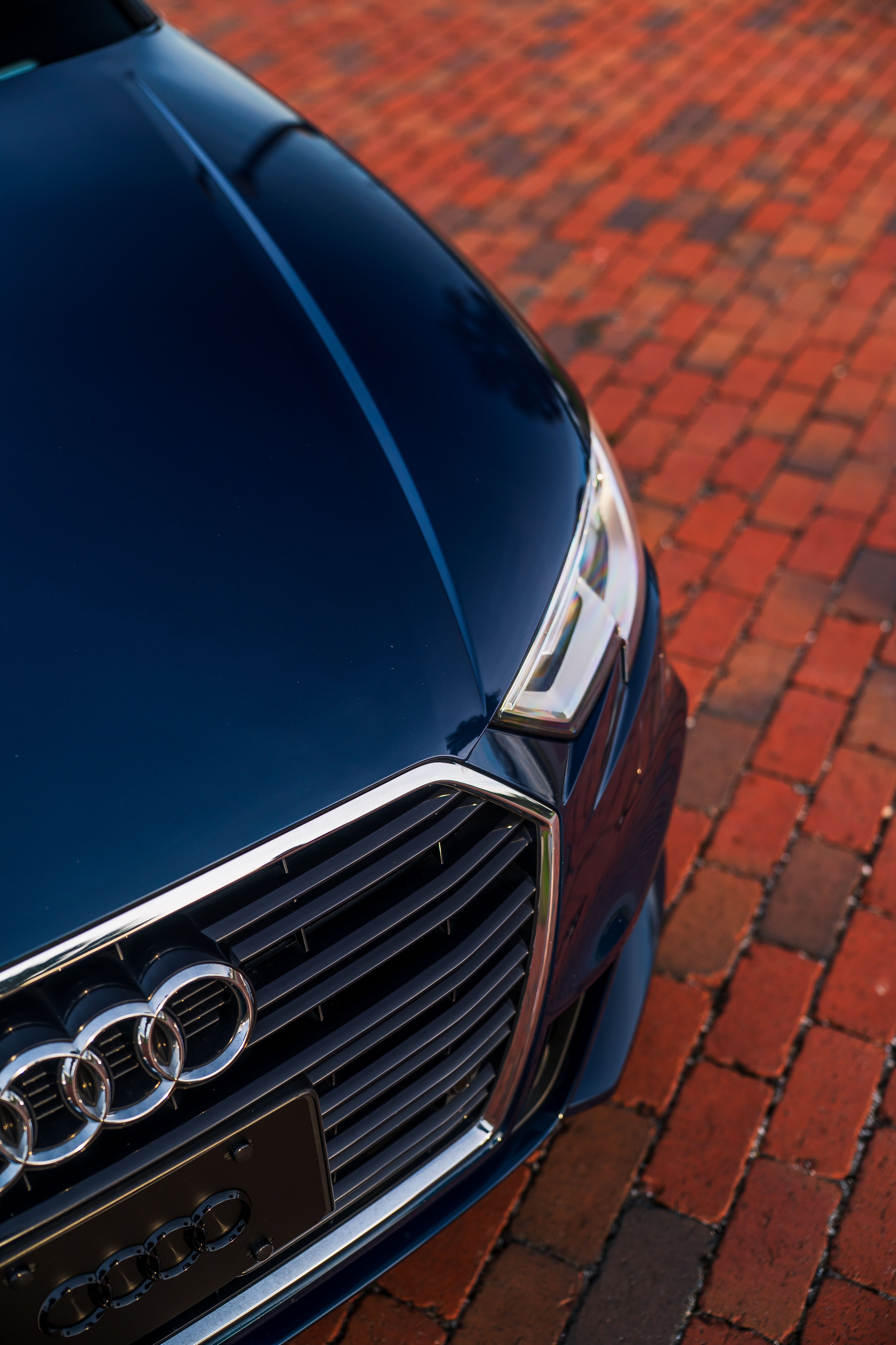Close-Up of Luxury Car Front on Brick Road · Free Stock Photo