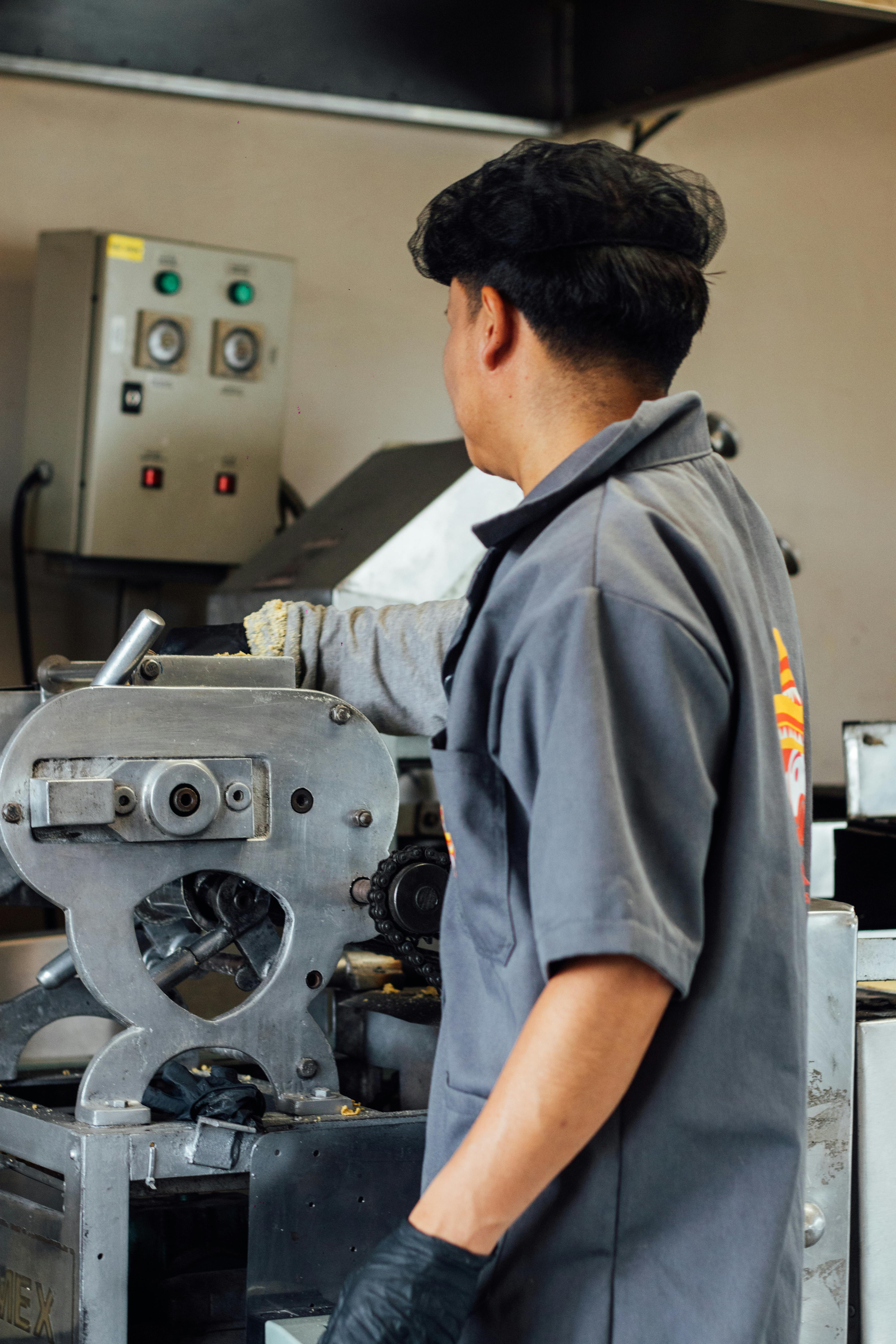 Worker Operating Industrial Machinery in Factory Setting · Free Stock Photo