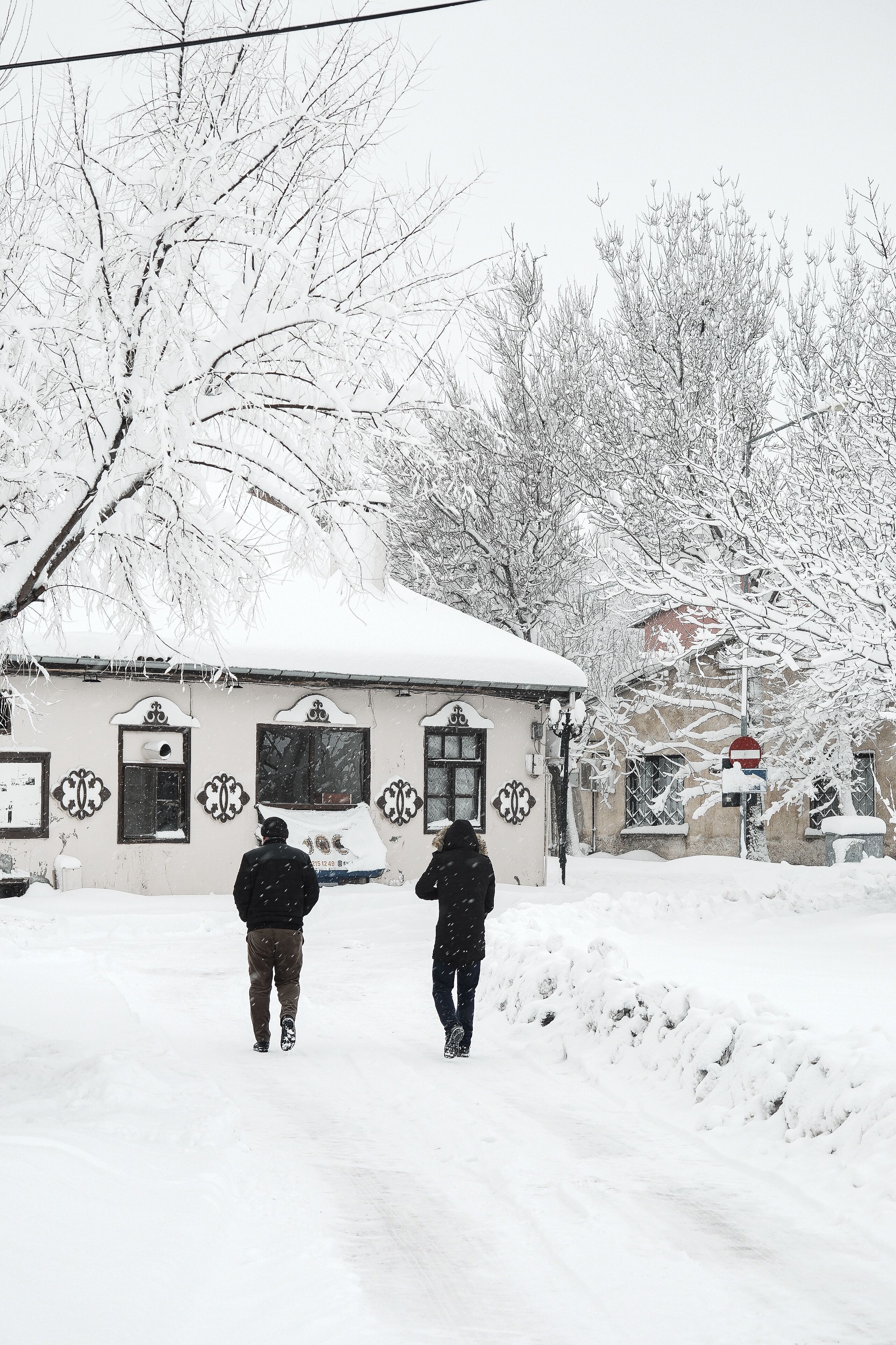 Two People Walking in Snowy Winter Town · Free Stock Photo