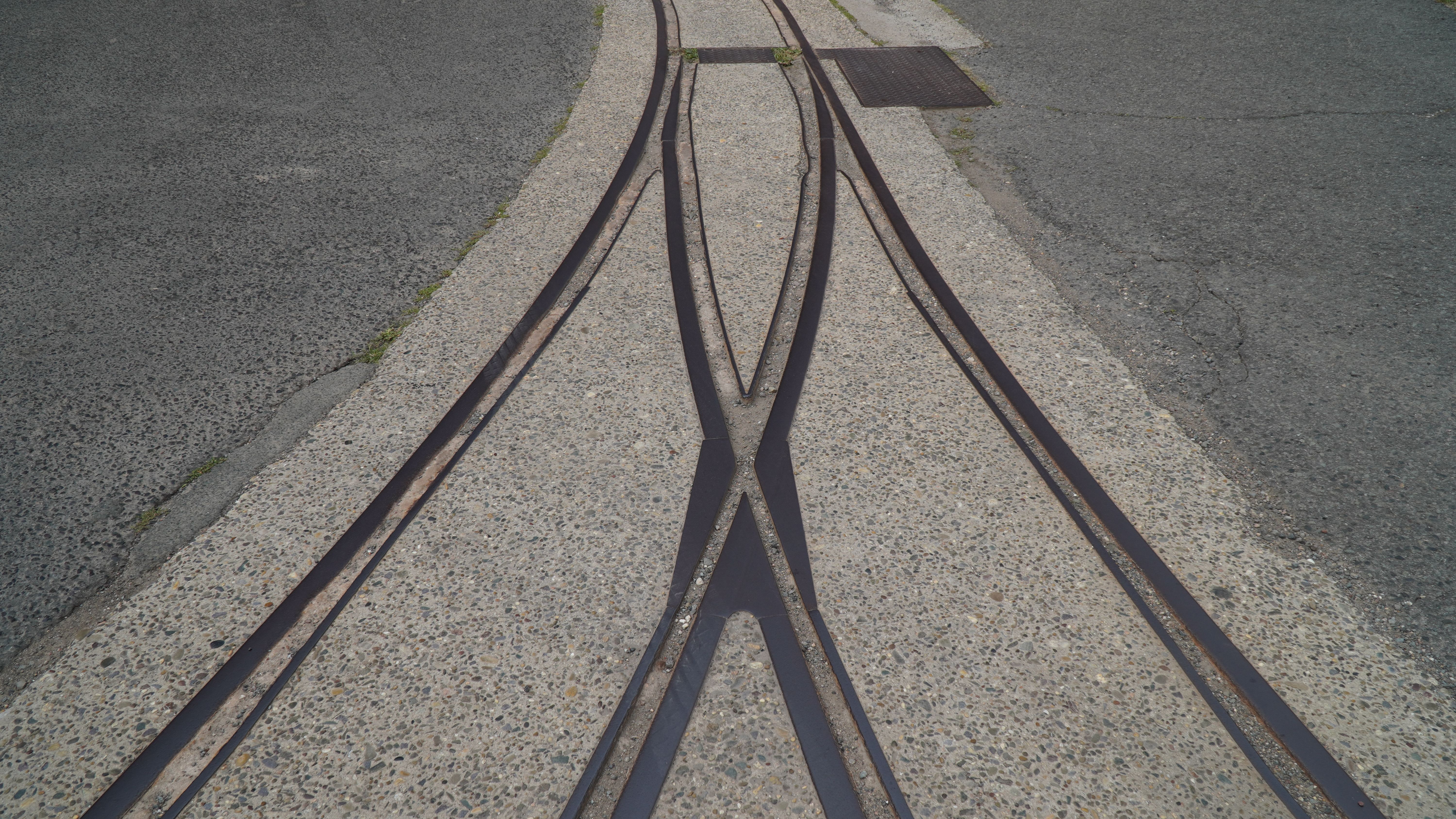 Intersection of Steel Rail Tracks on Pavement · Free Stock Photo
