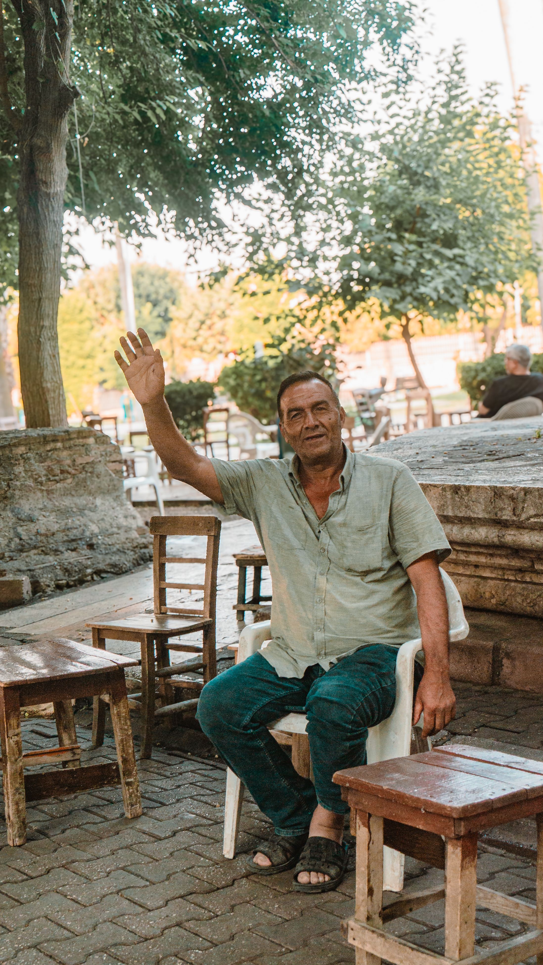 Man waving in outdoor cafe setting · Free Stock Photo