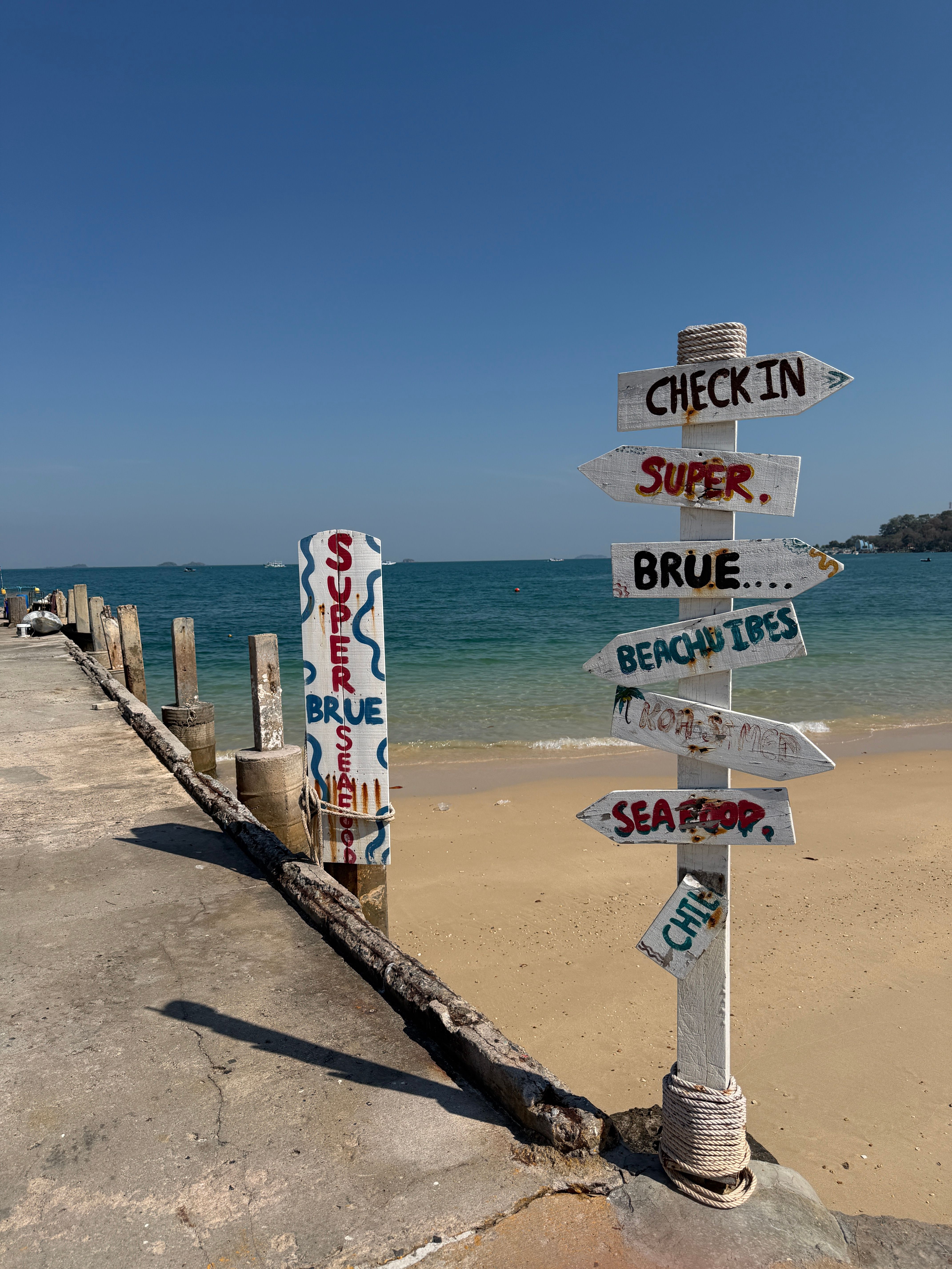 Scenic Beach Pier with Colorful Signpost · Free Stock Photo