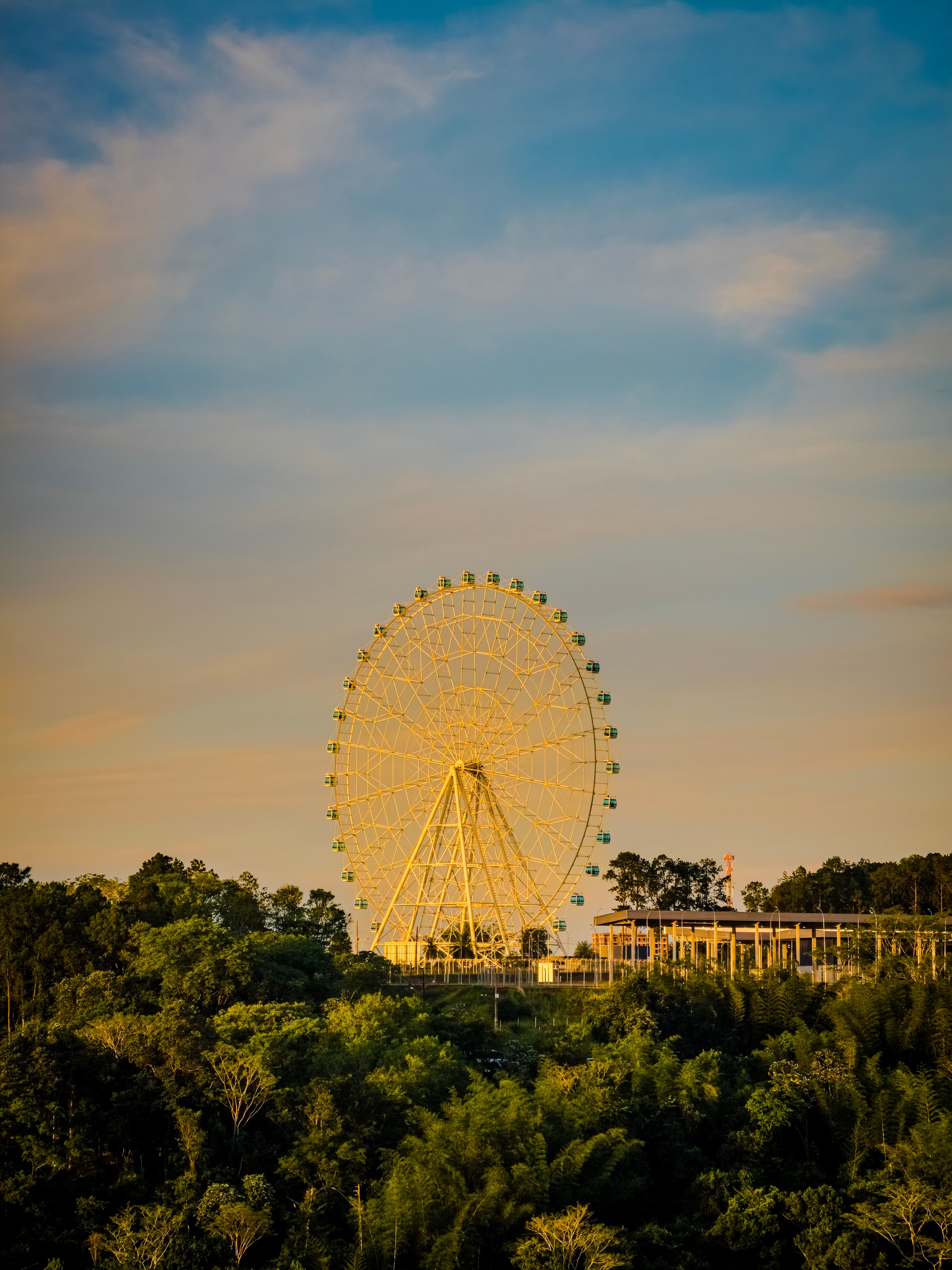 Golden Ferris Wheel at Sunset Over Lush Landscape · Free Stock Photo