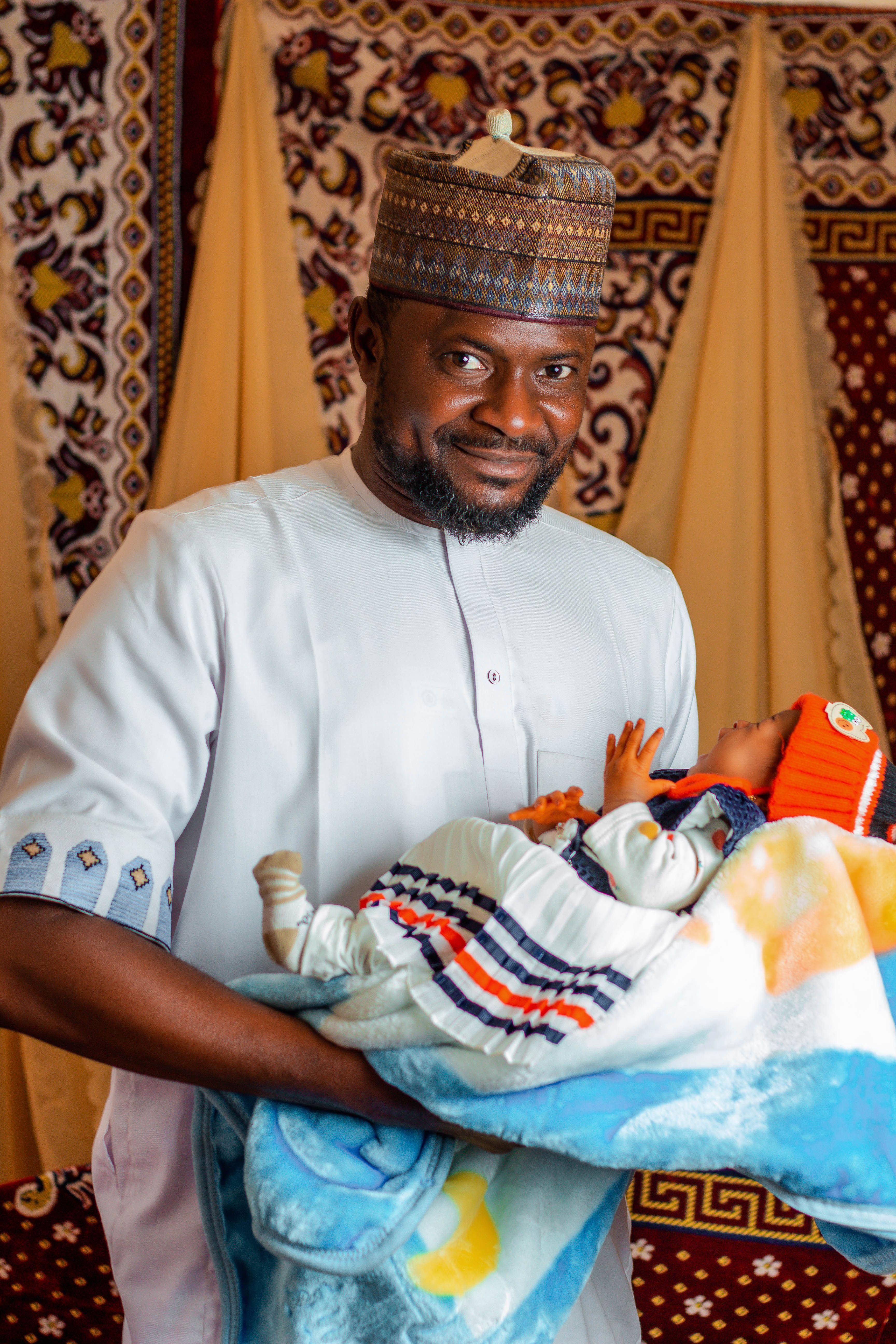 Proud Father Holding Newborn in Traditional Setting · Free Stock Photo