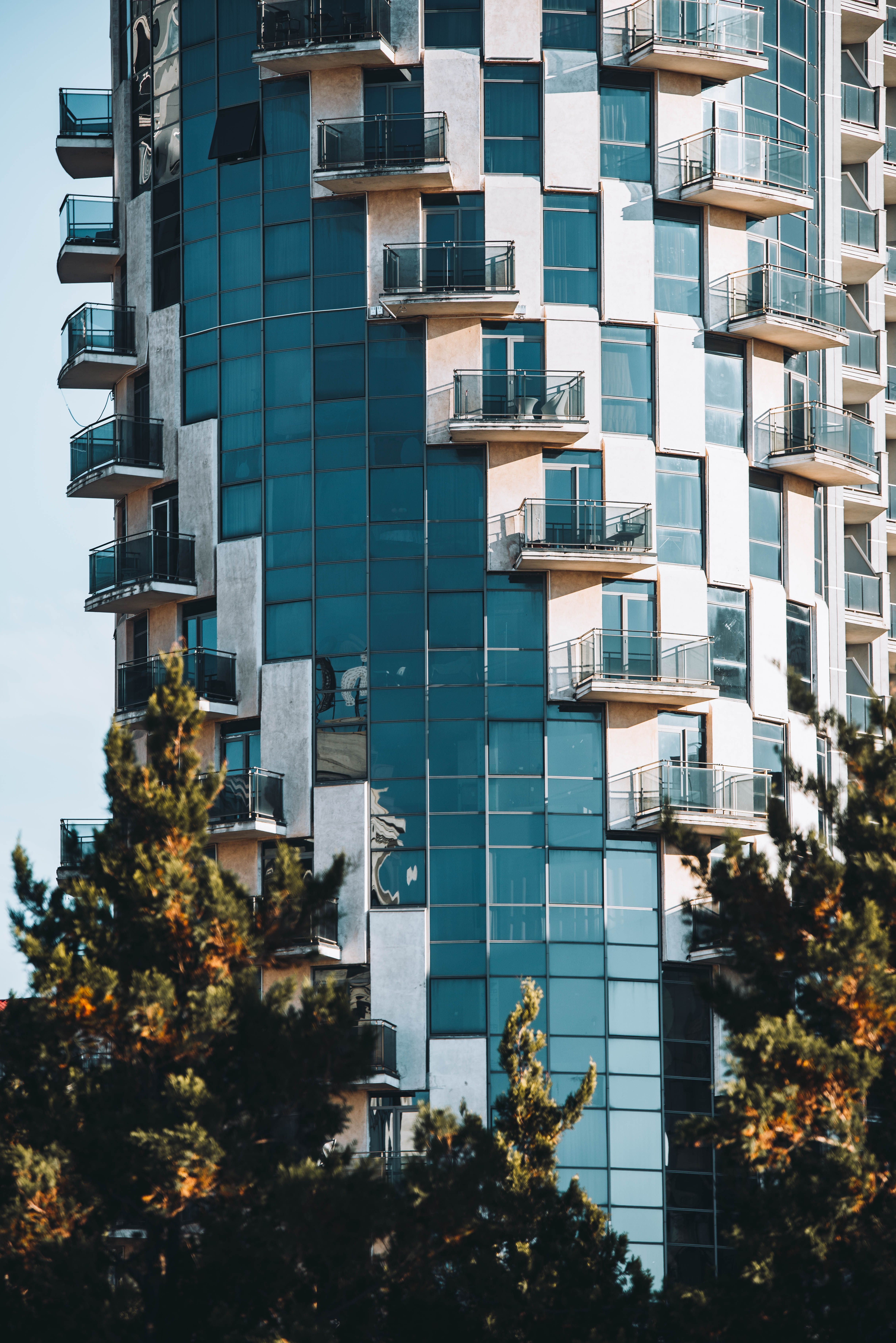 Modern High-Rise with Glass Balconies and Trees · Free Stock Photo