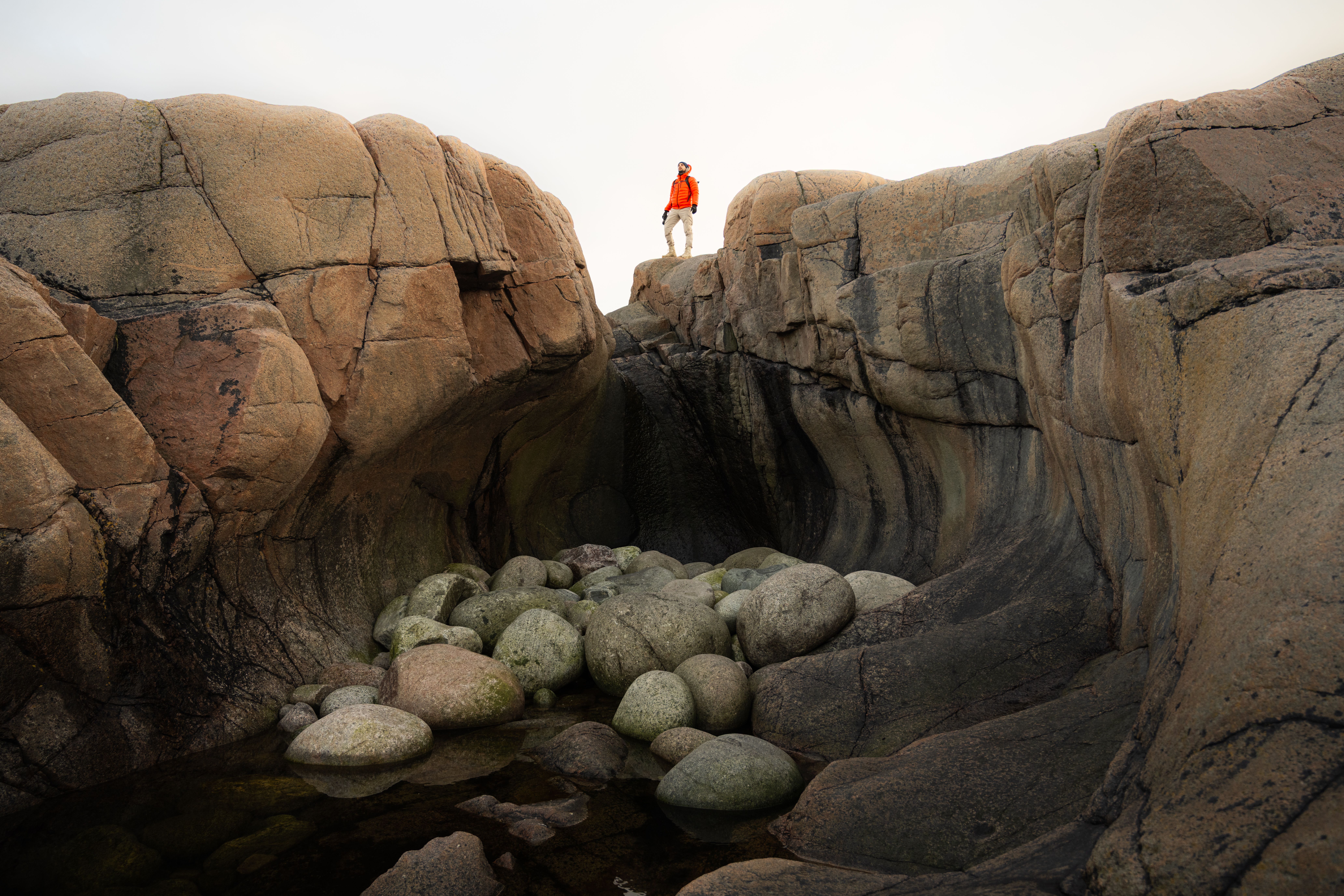 Adventurer Standing on Rugged Rock Formation · Free Stock Photo